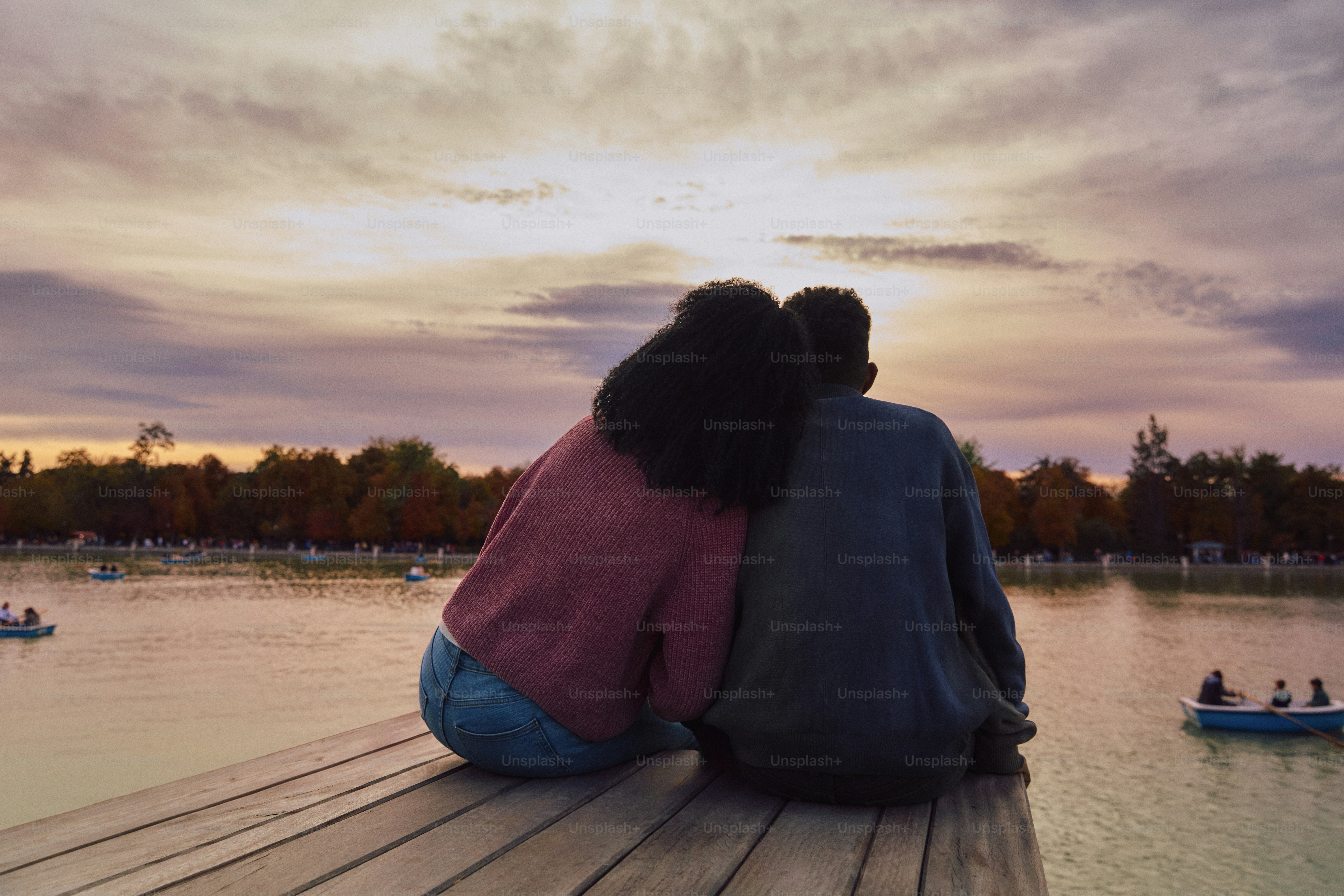 Two people sitting on a dock watching boats go by photo – Love Image on ...