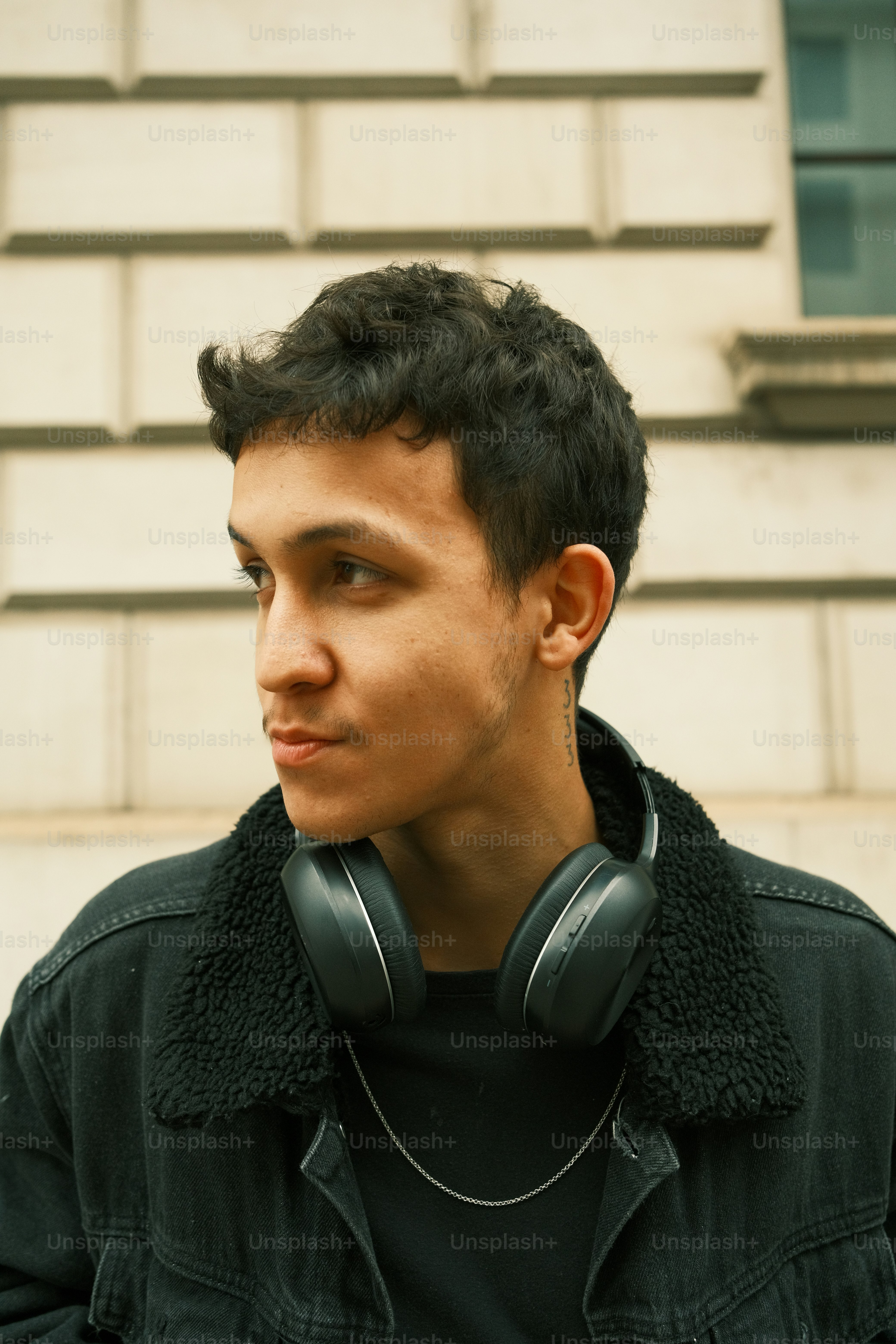 A man wearing headphones standing in front of a building photo – Profile Image on Unsplash
