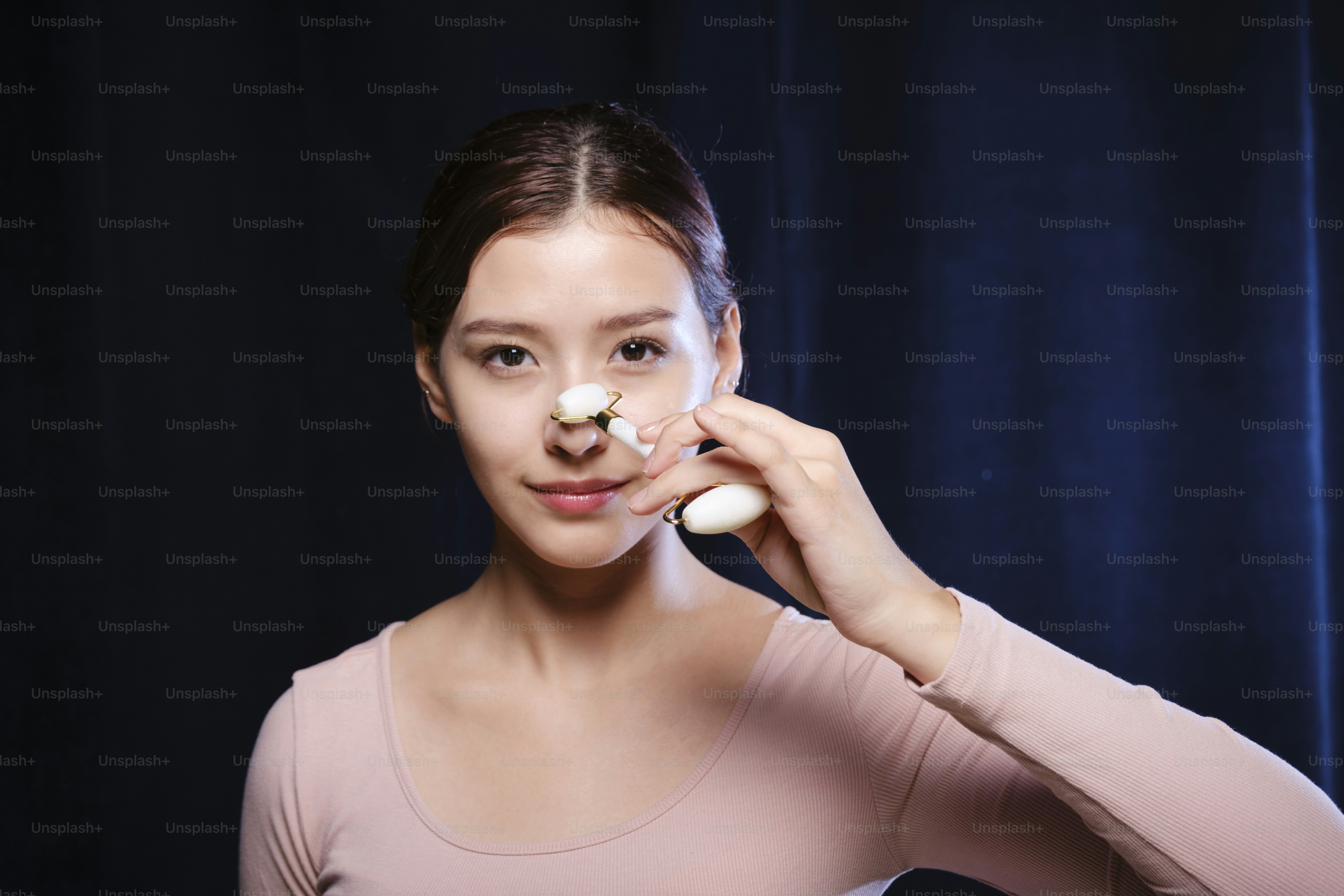 A woman is holding a white object in front of her face photo – Skincare ...