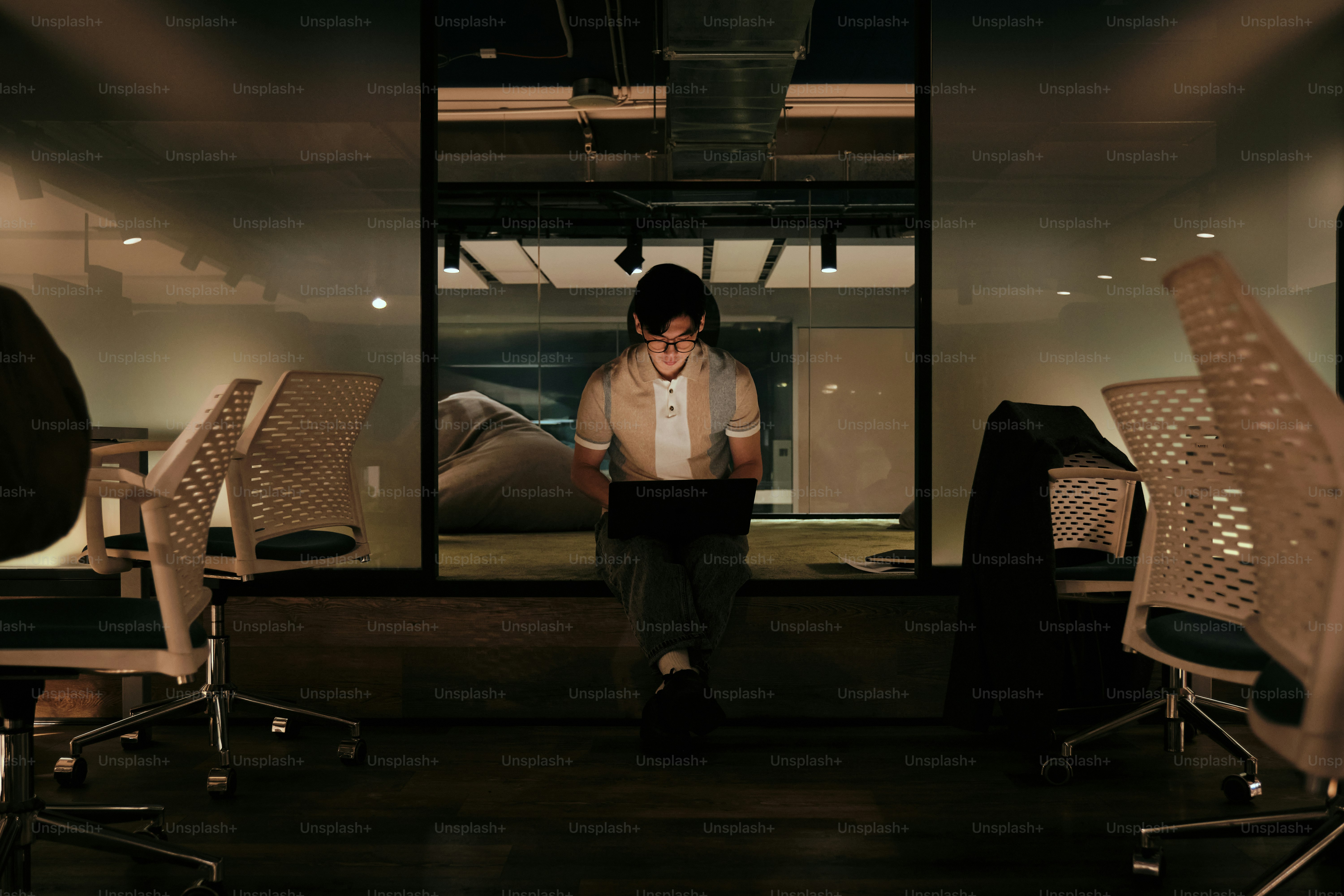 A man sitting in a chair using a laptop computer photo – Office Image ...