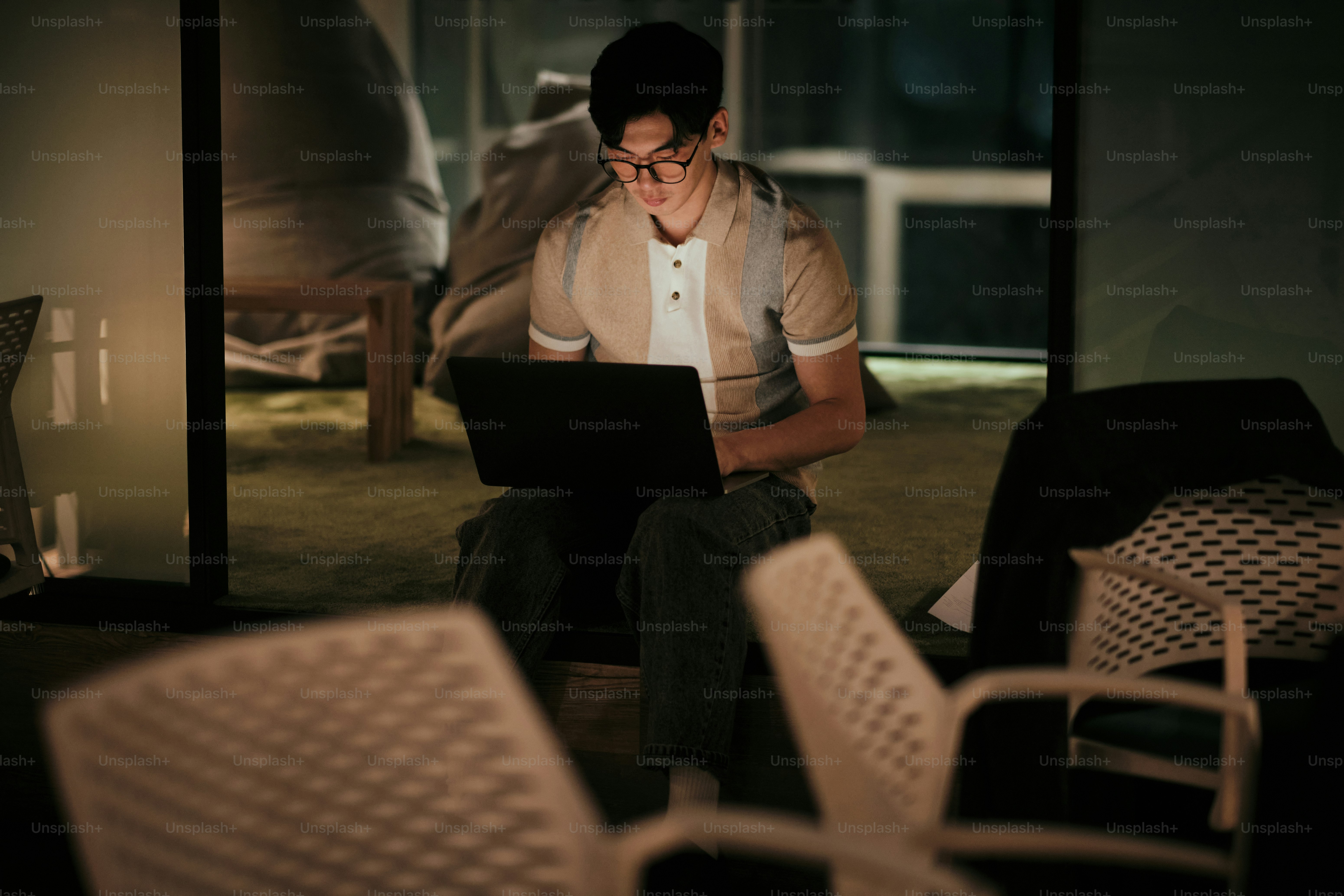 A man sitting in a chair using a laptop computer photo – Office Image ...