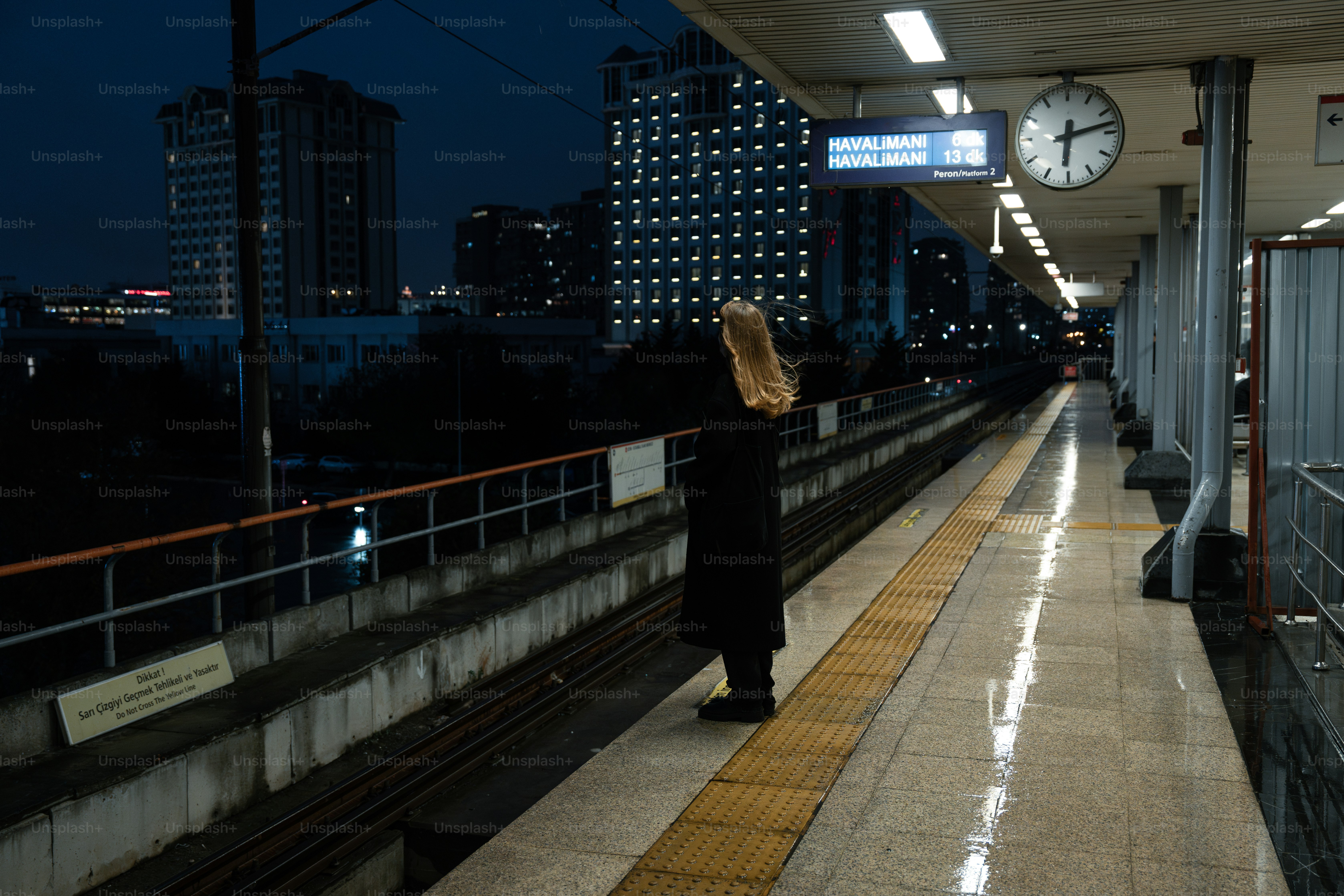 A woman standing on a train platform at night photo – Urban solitude ...