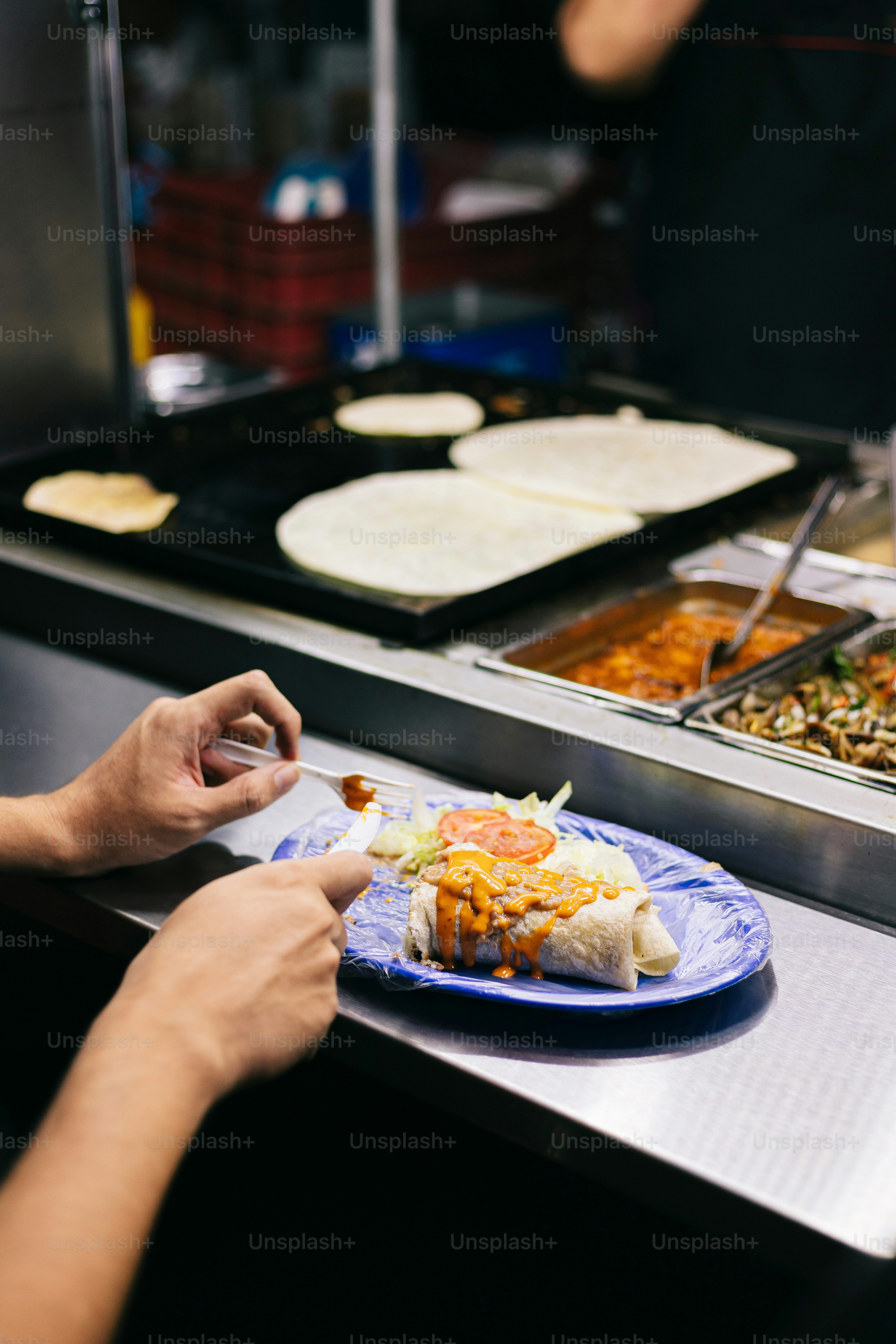 A person sitting at a counter with a plate of food photo – Tacos Image ...