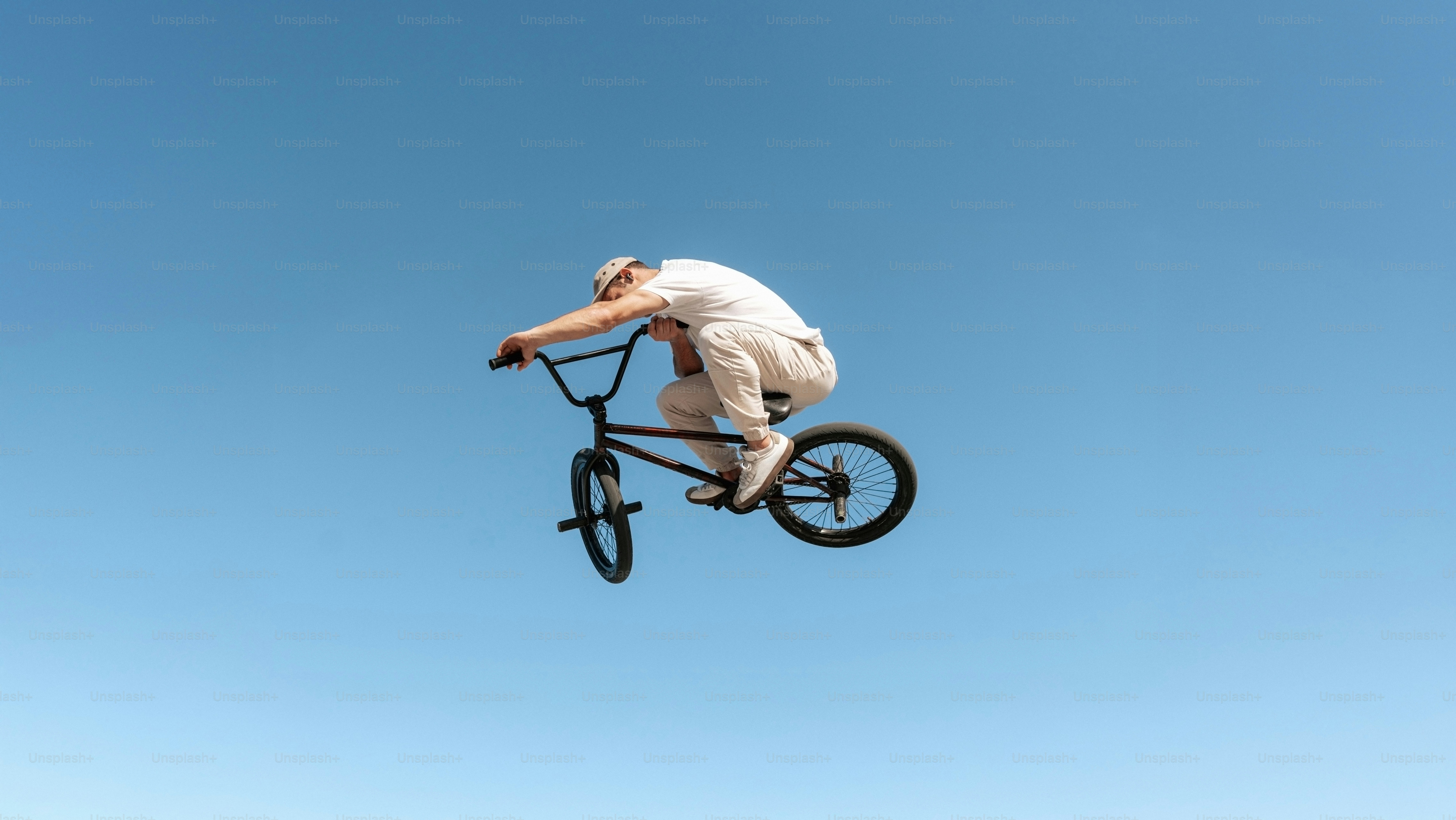 A man riding a bike while flying through the air photo – Bike Image on ...