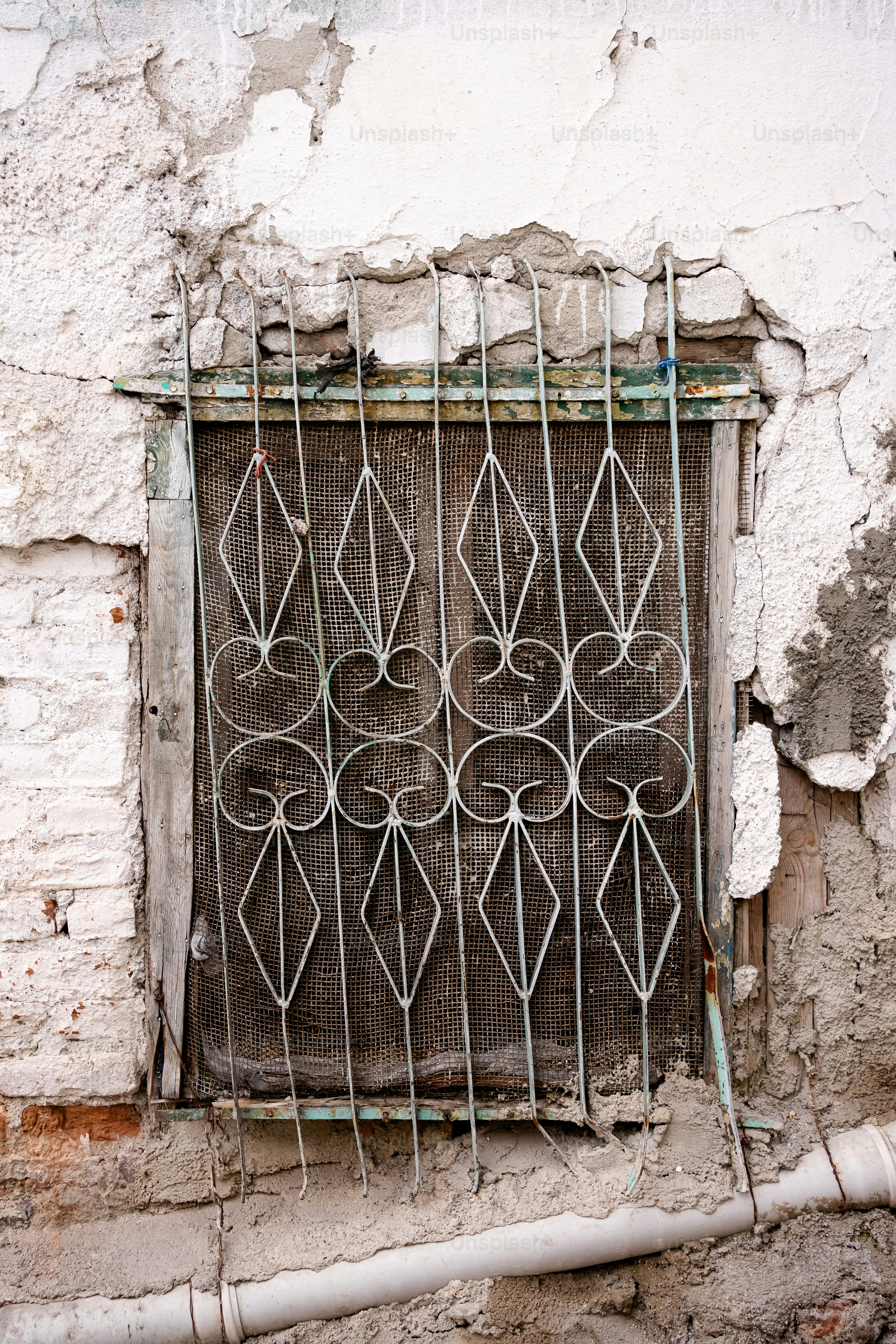 An old window with iron bars on the side of a building photo – Urban ...