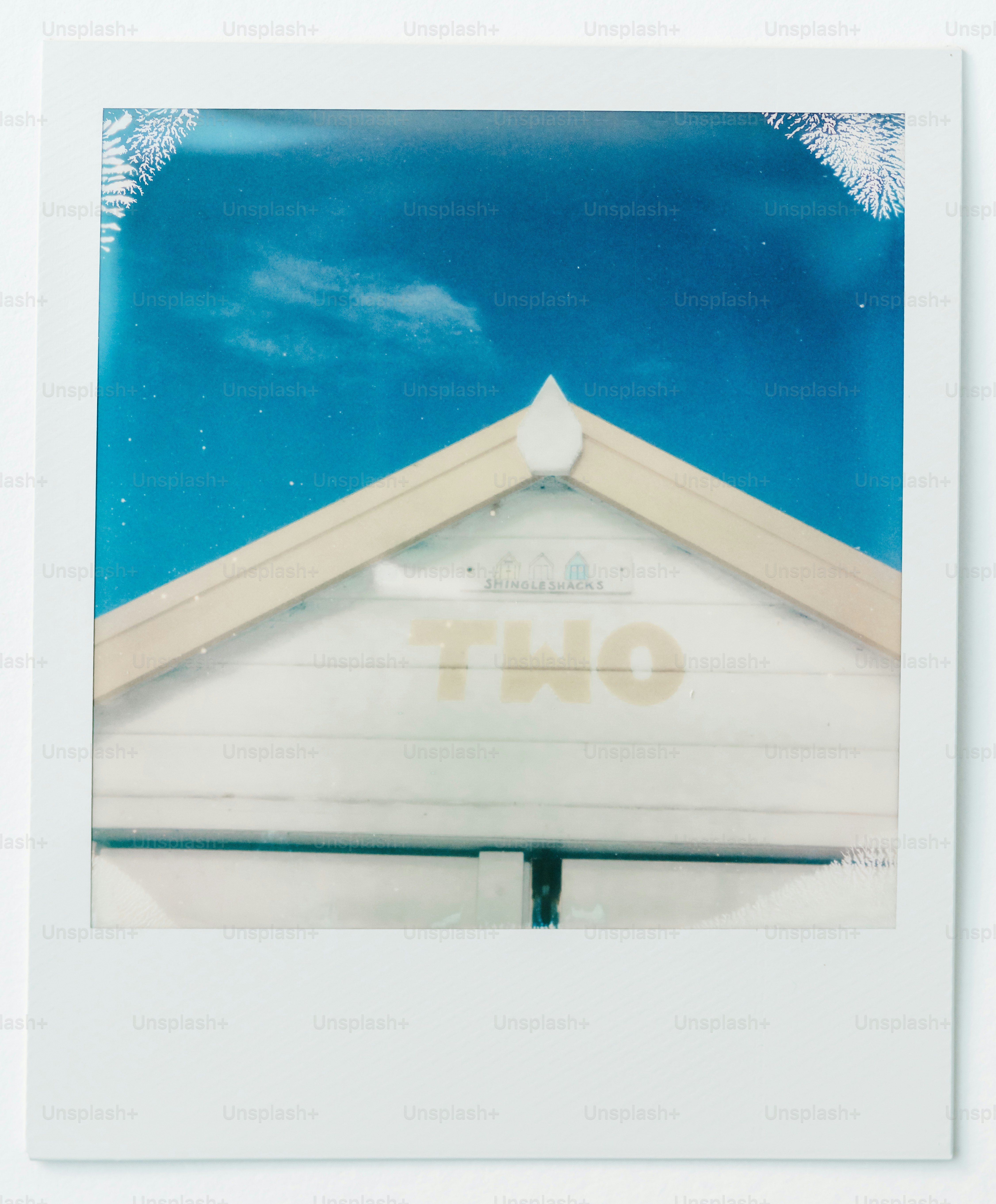 A polaroid photograph of a white building with a blue sky in the ...
