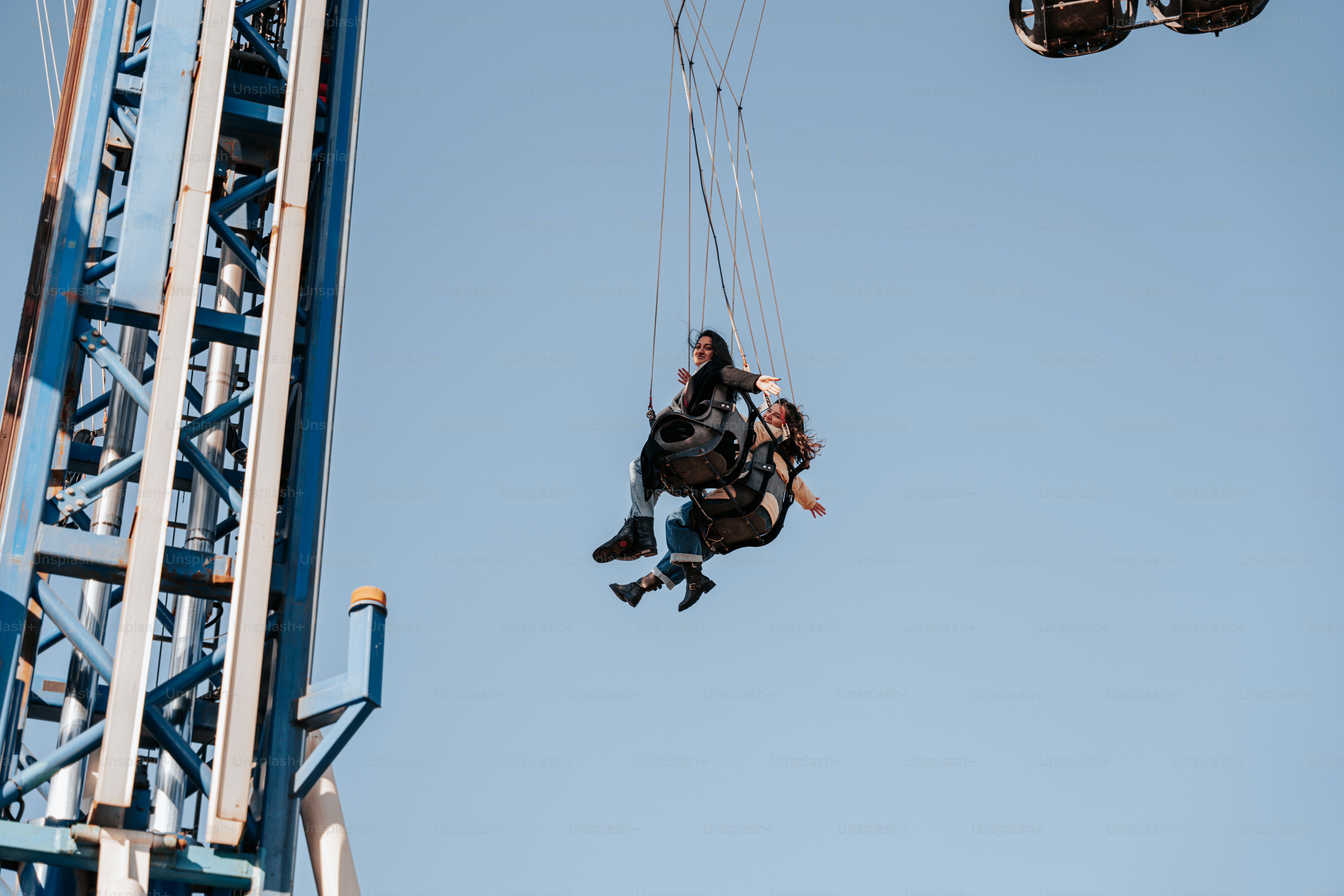 A man riding a zip line on top of a roller coaster photo – Fairground ...