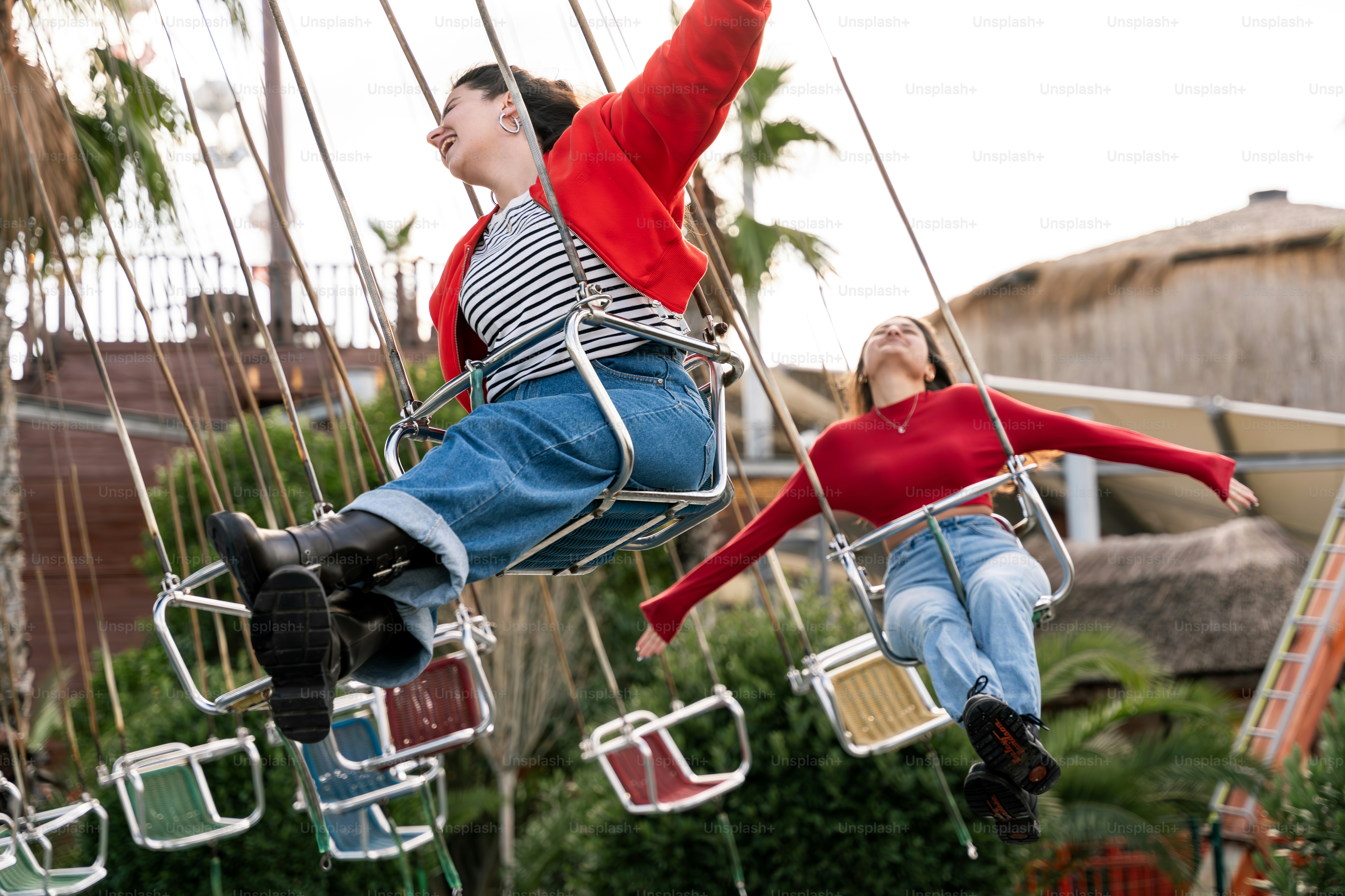 A couple of people riding on top of a zip line photo – Fairground ride ...