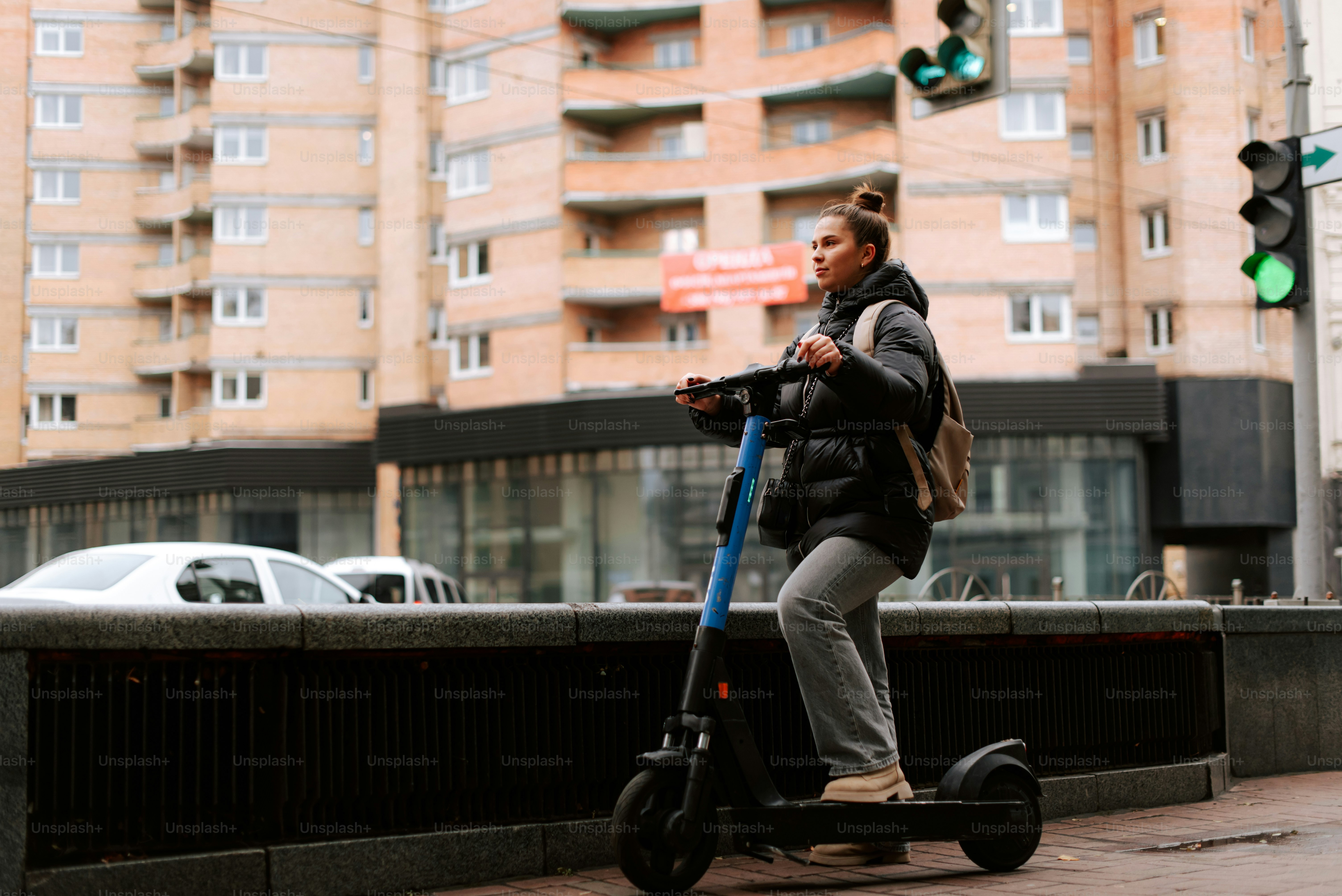 A man riding a scooter on a city street photo – Professional person ...