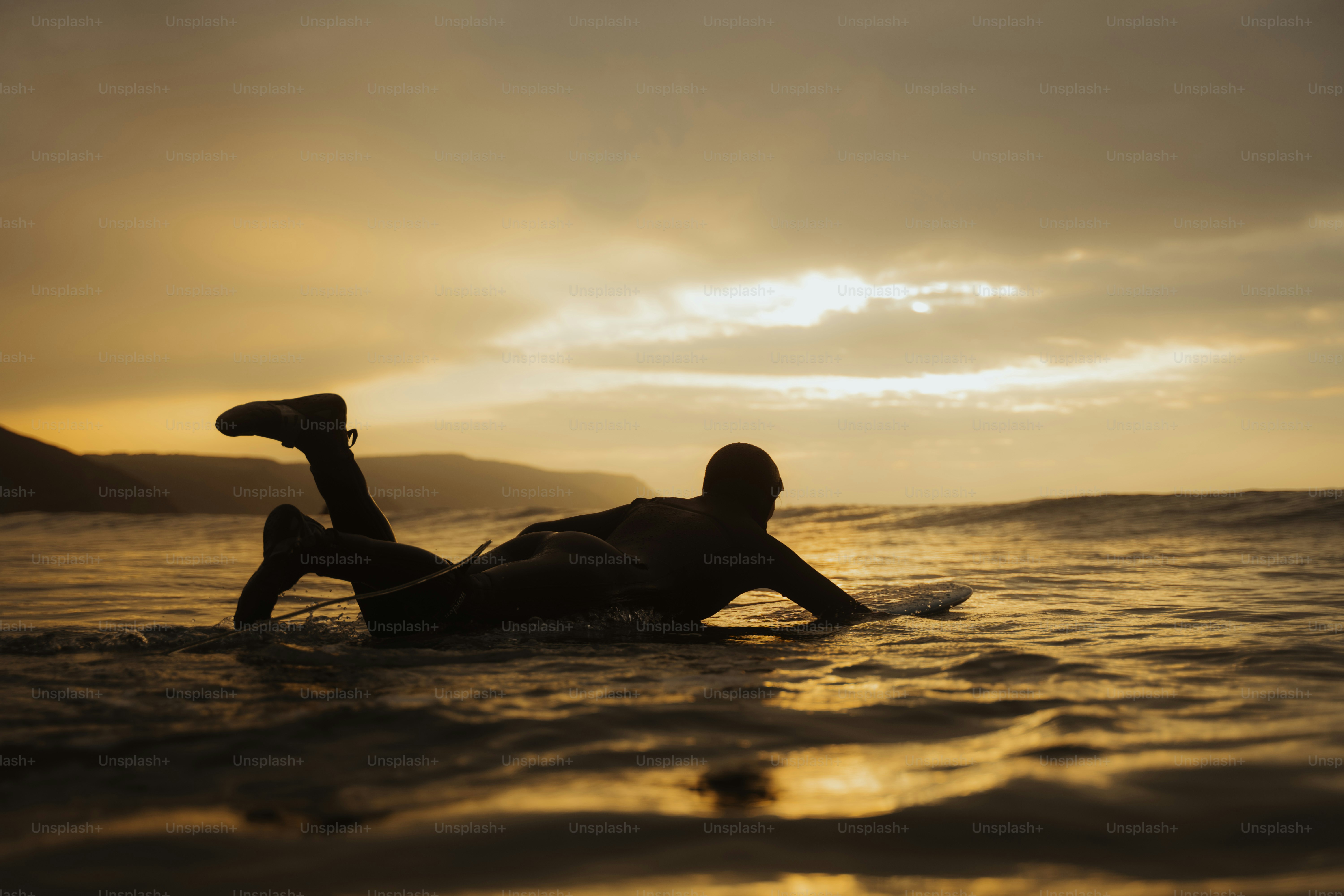 A person laying on a surfboard in the water photo – Travel Image on ...