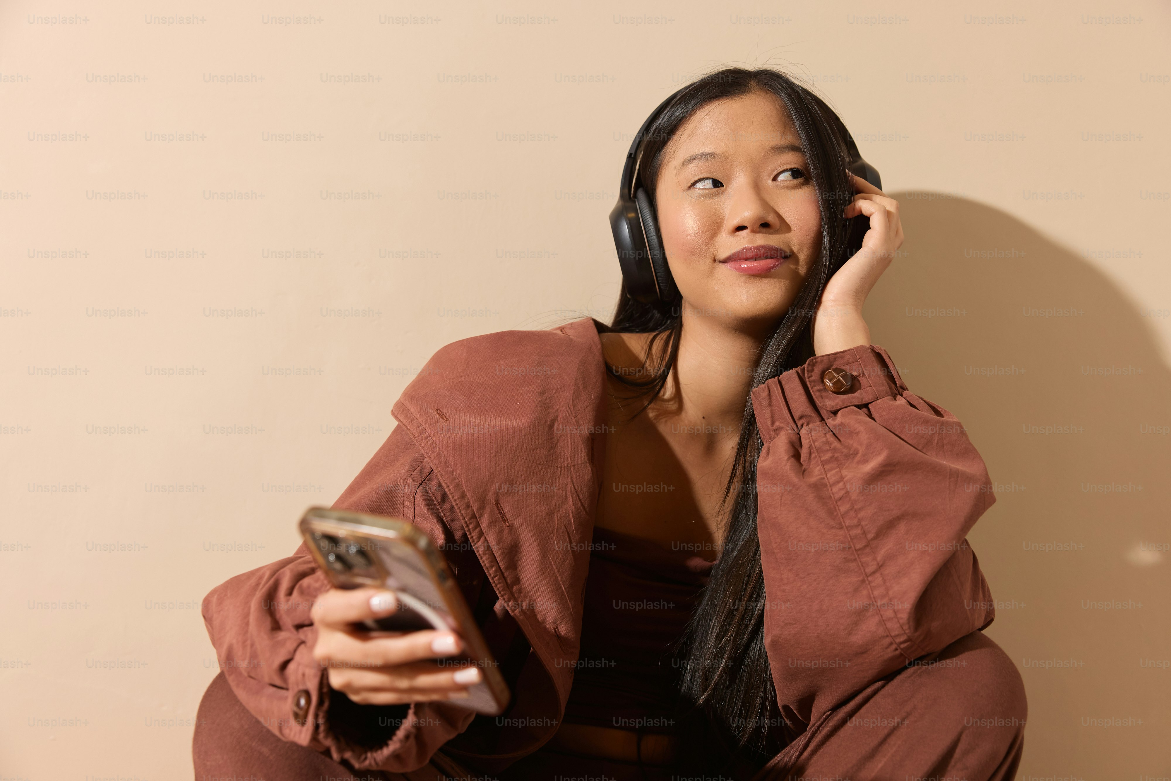 Eine Frau, die auf dem Boden sitzt und mit einem Handy telefoniert Foto ...