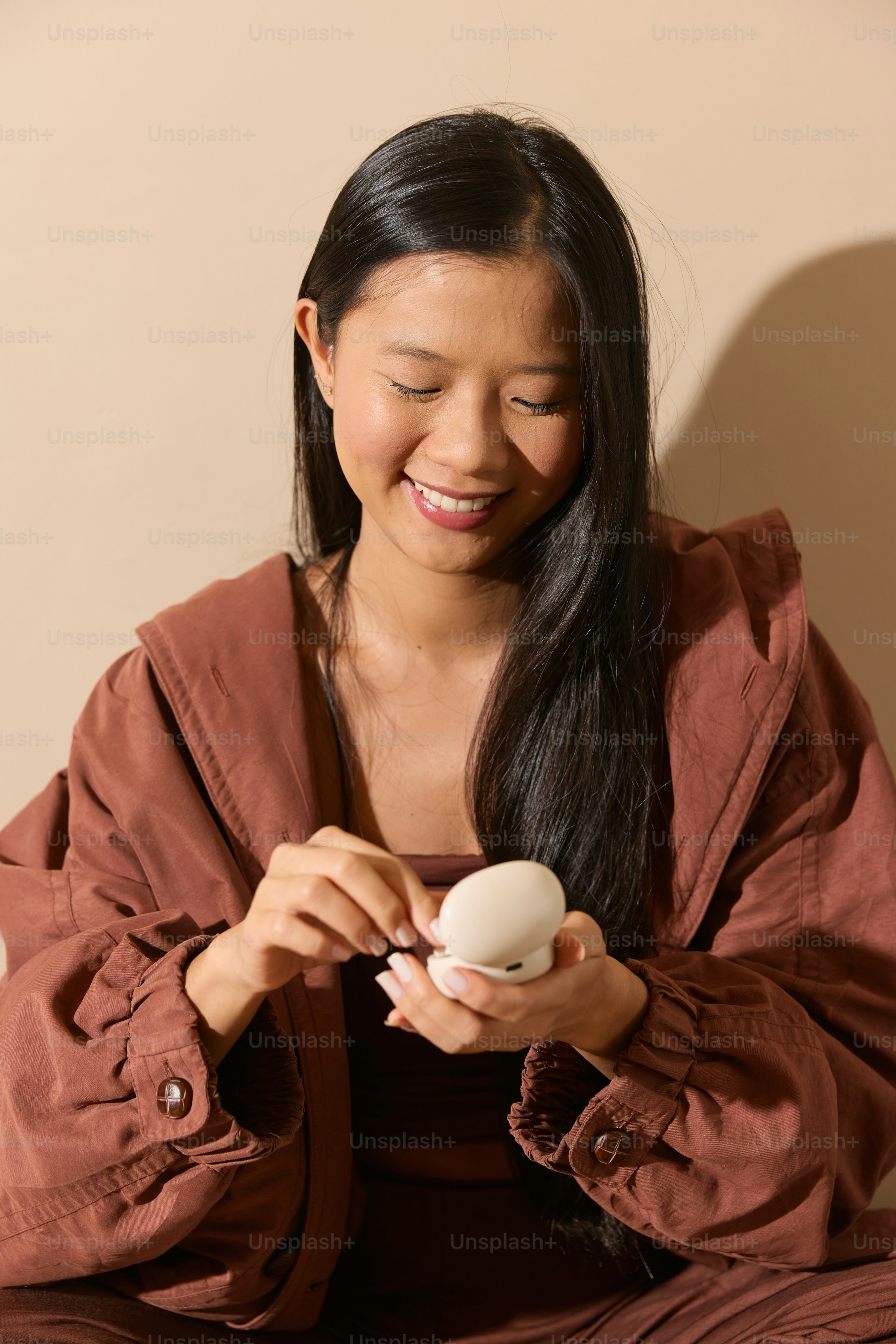 A woman sitting on the floor holding a white object photo – Listening ...