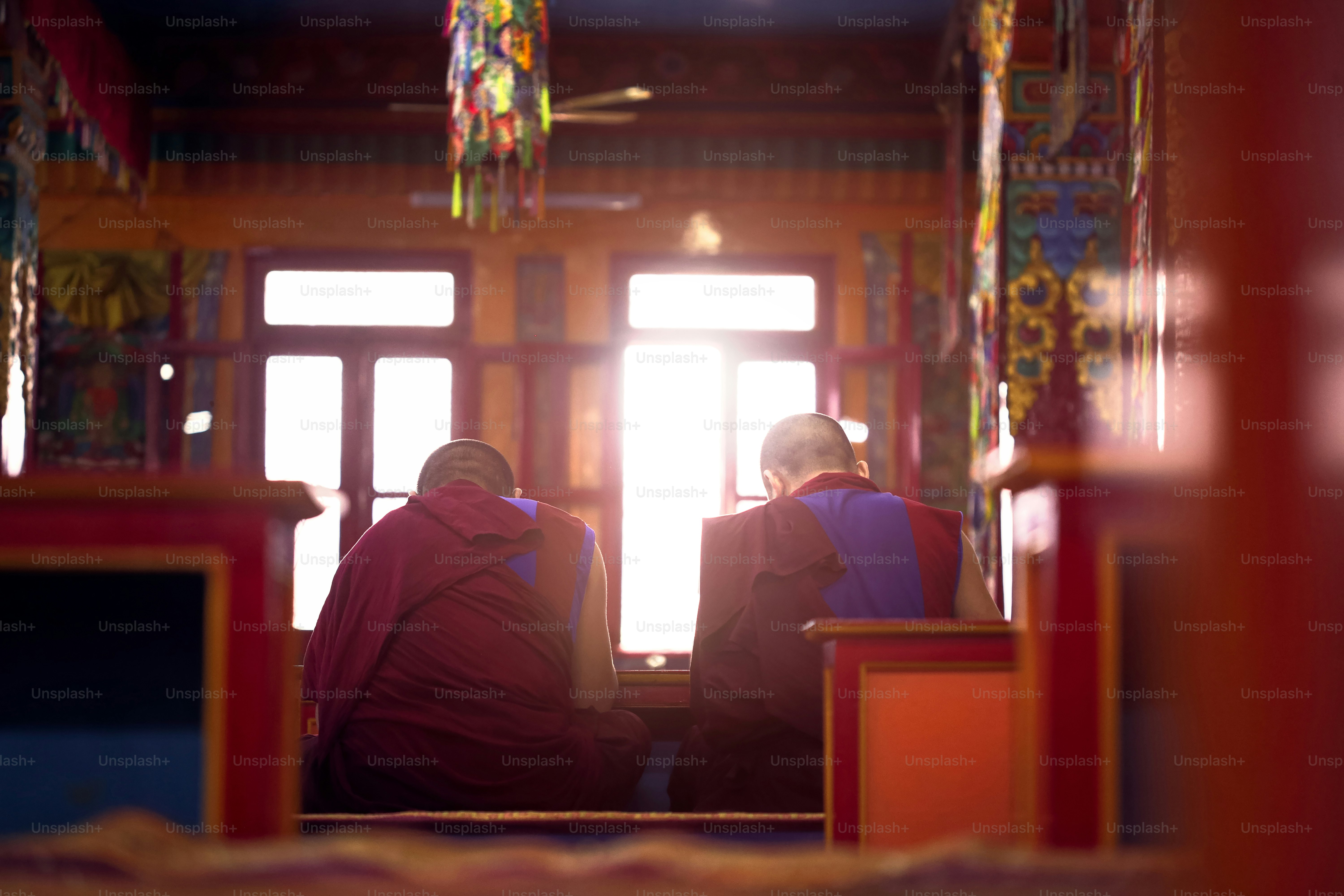 Two people sitting at a table in a room photo – The menri monastery ...