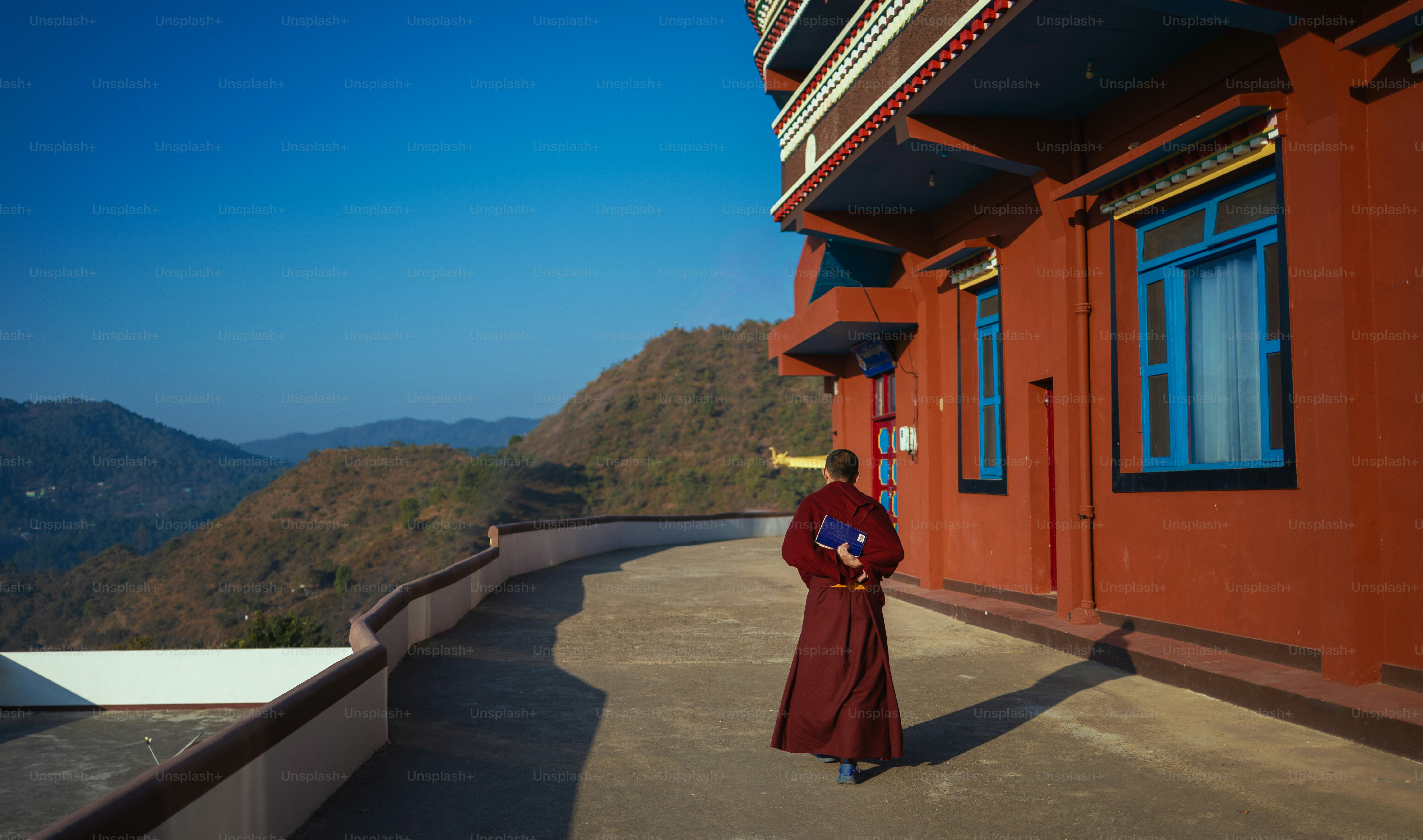 A monk standing in front of a red building photo – Monk Image on Unsplash