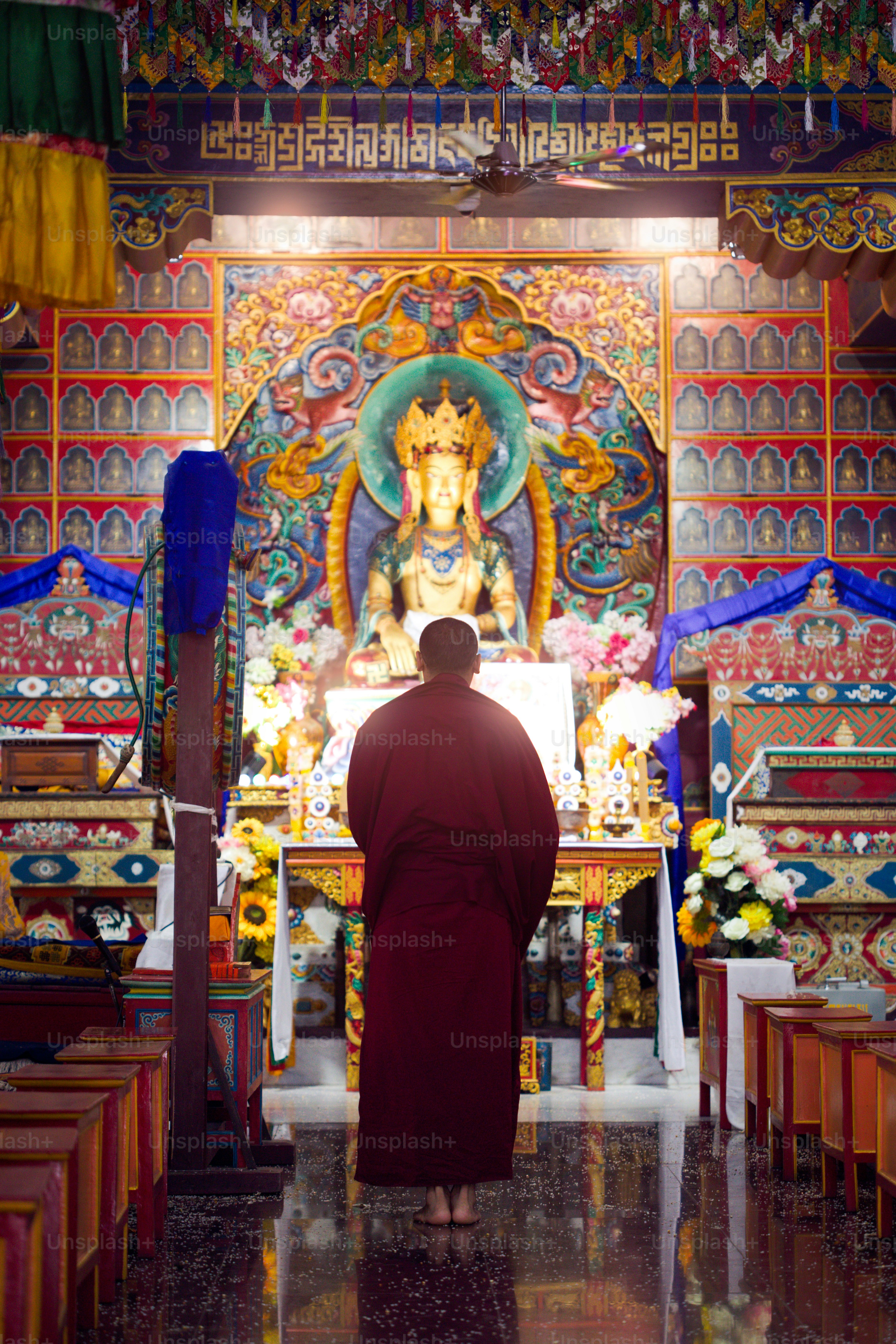 A monk standing in front of a shrine photo – The menri monastery Image ...