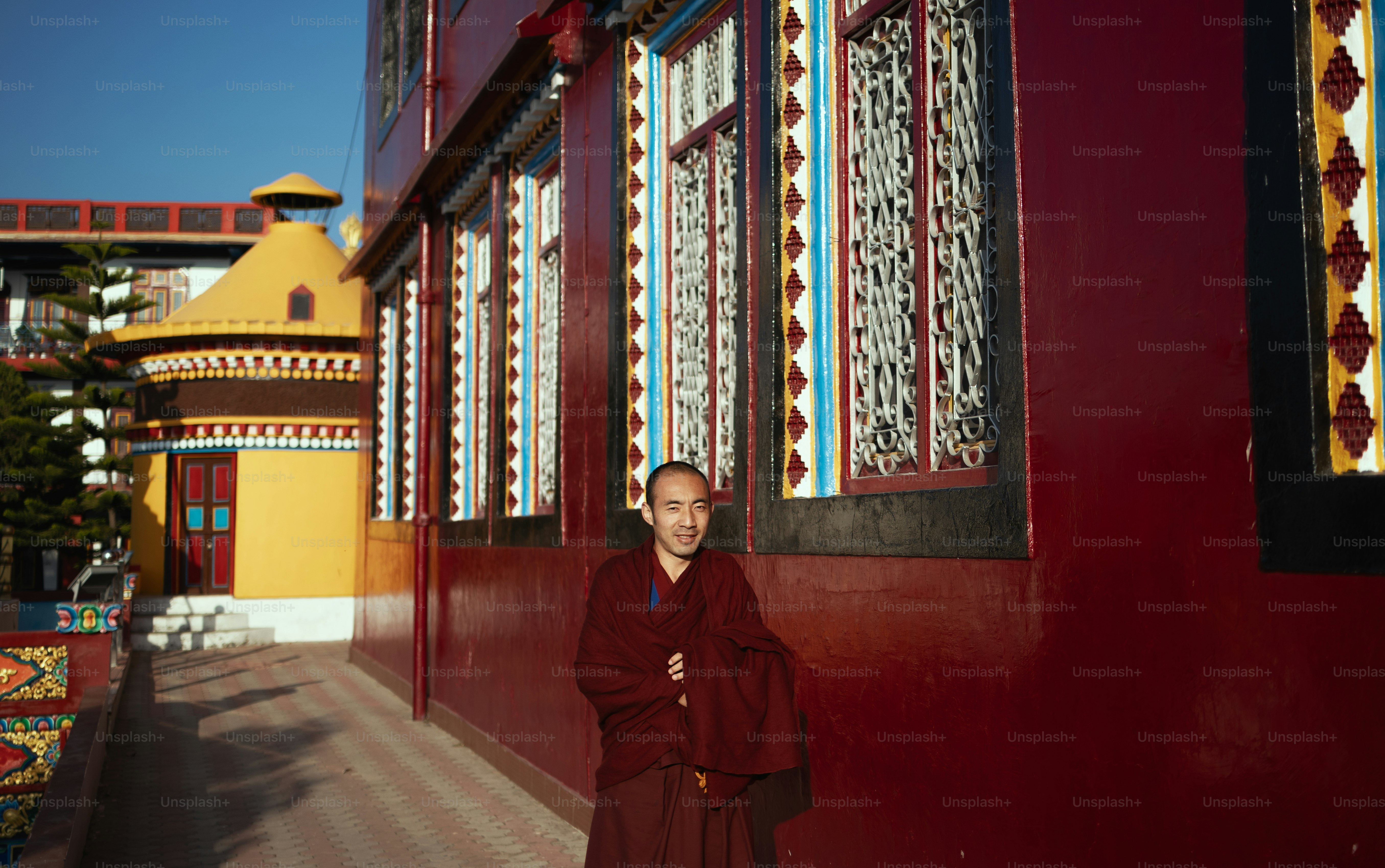 A man standing in front of a red building photo – The menri monastery ...