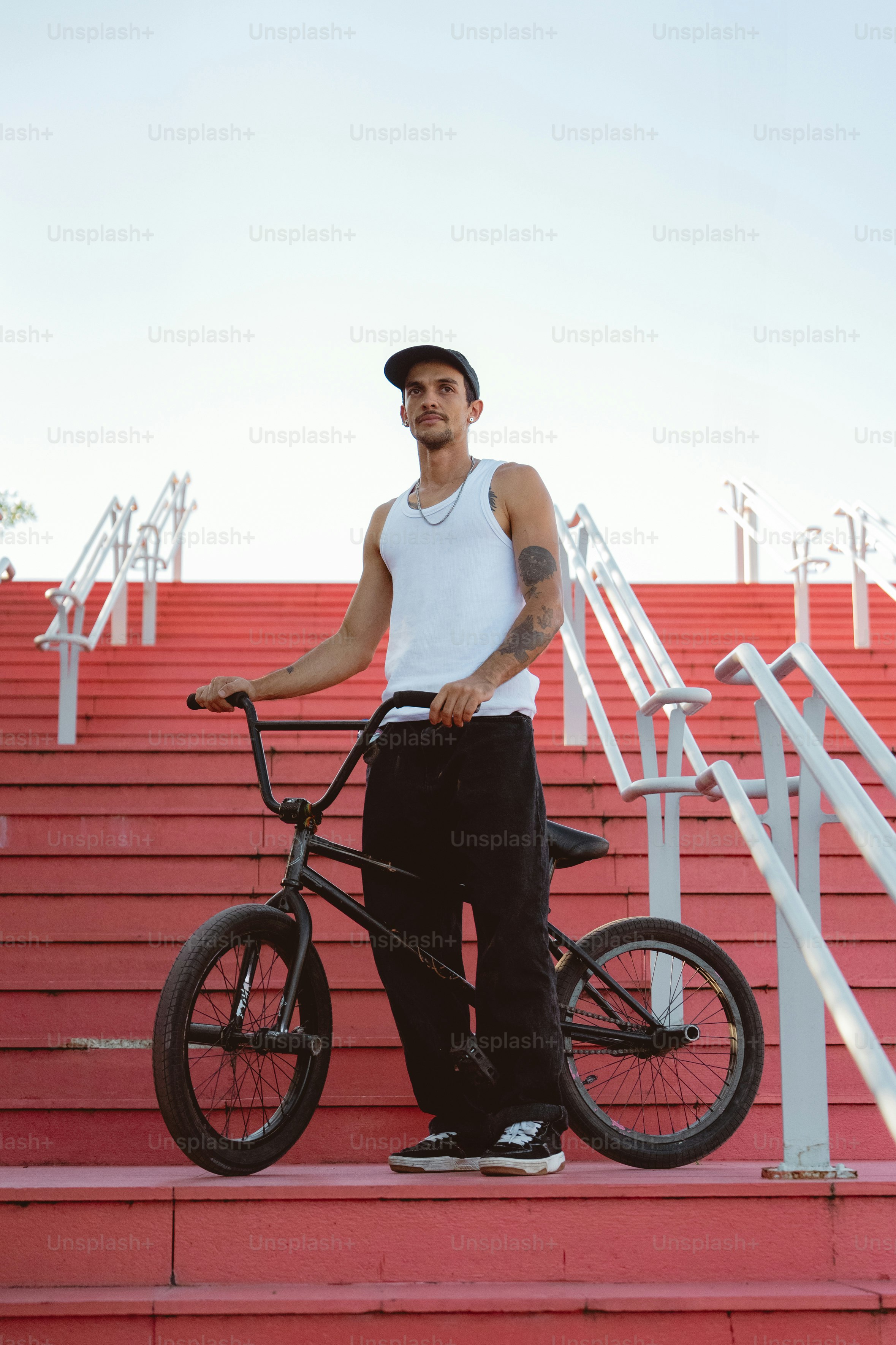 A man standing next to a bike on top of a set of stairs photo – Bike ...