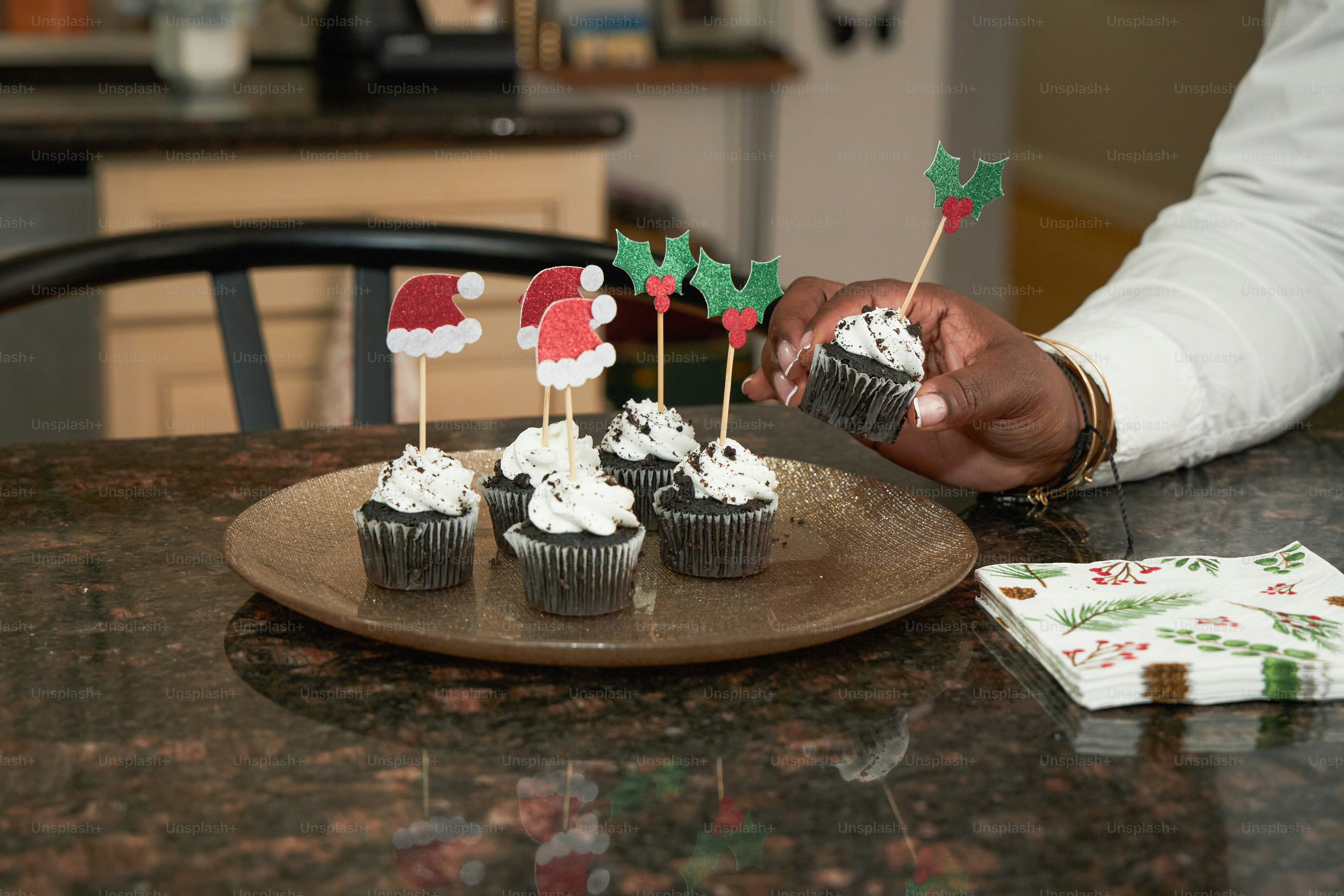 A person putting cupcakes on a plate on a table photo – Cheers Image on ...