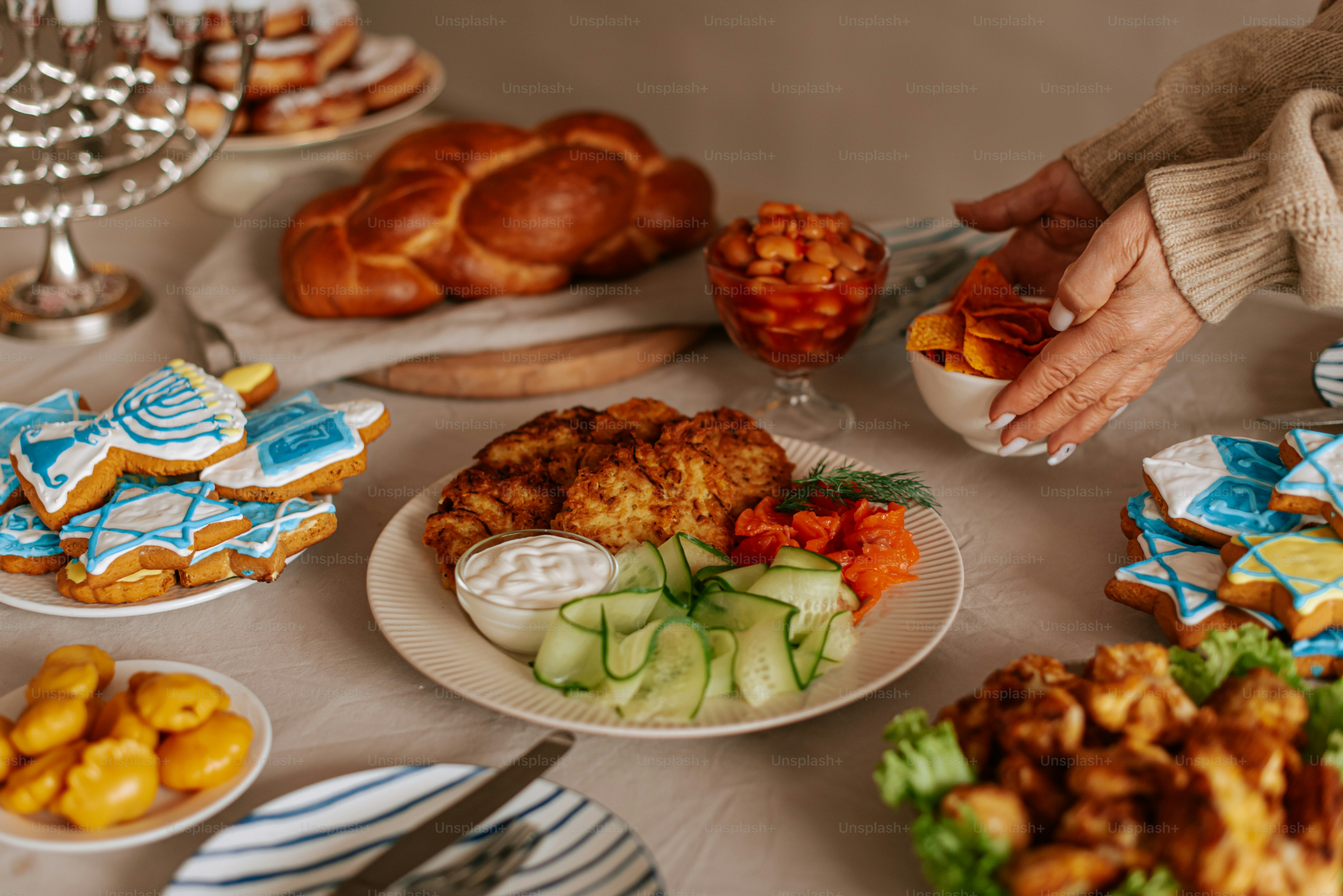 A table topped with plates of food and a menorah photo – Hanukkah food ...