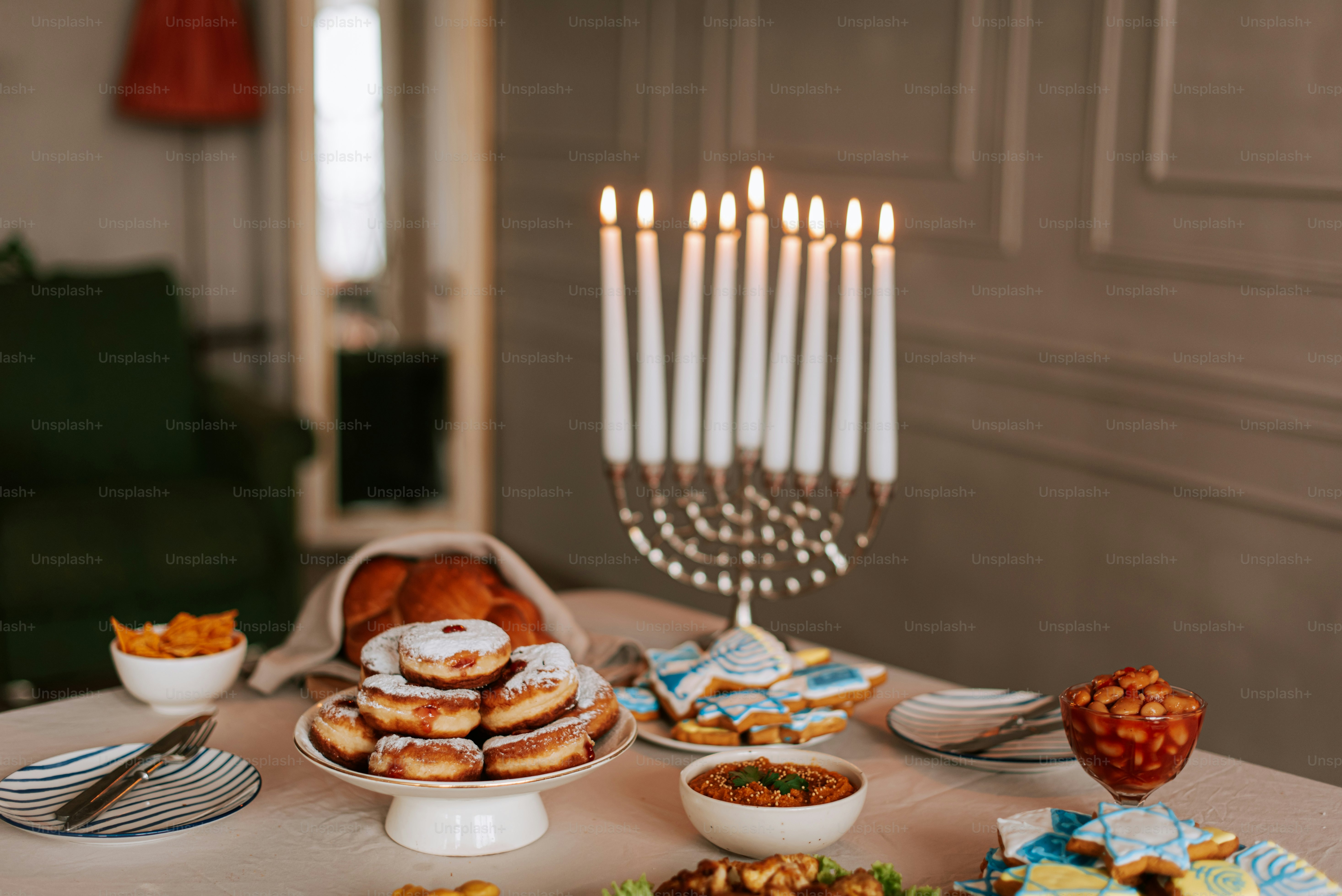 A table topped with plates of food and a menorah photo – Food Image on ...