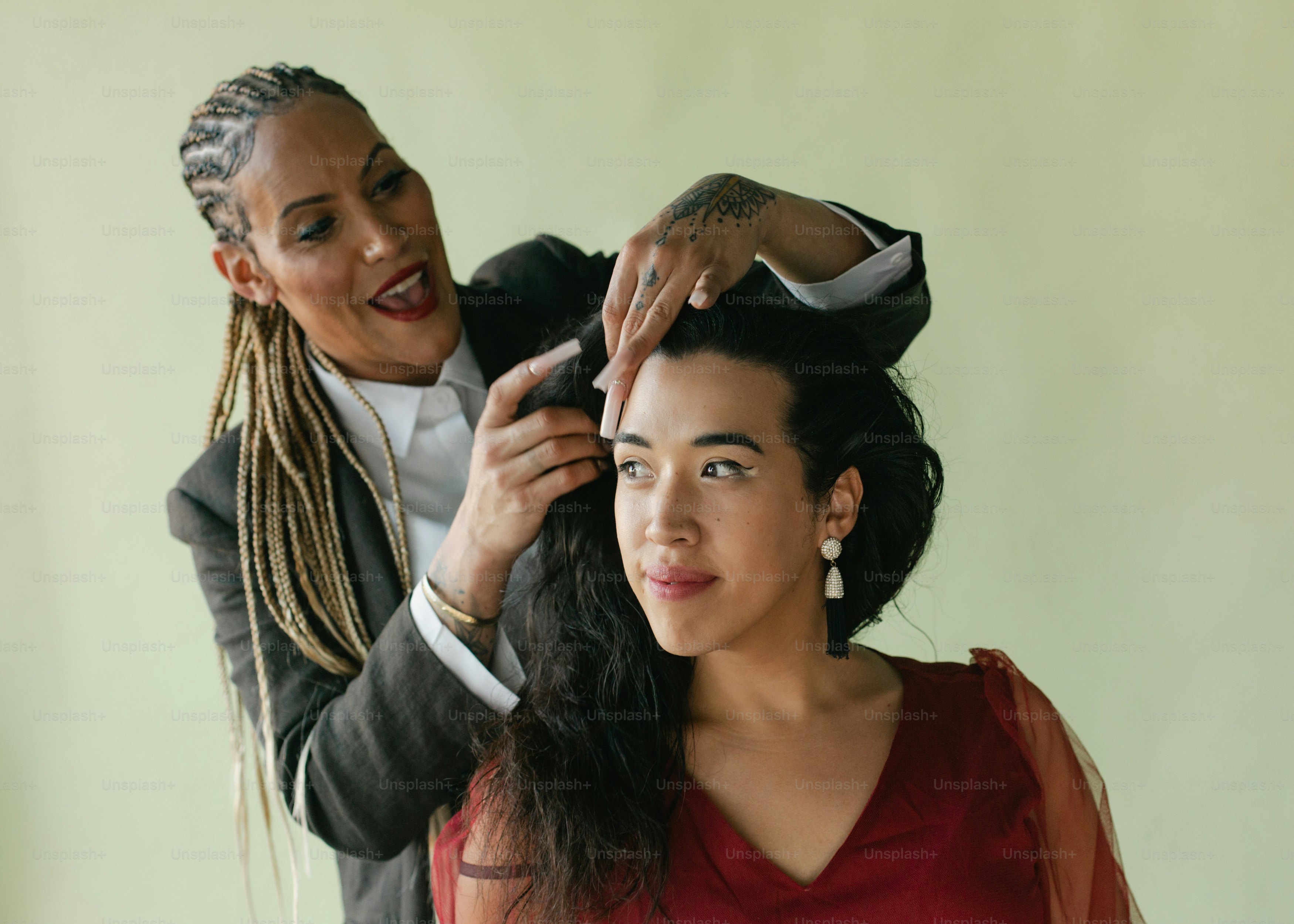 A woman getting her hair styled by a woman in a suit photo – Model ...