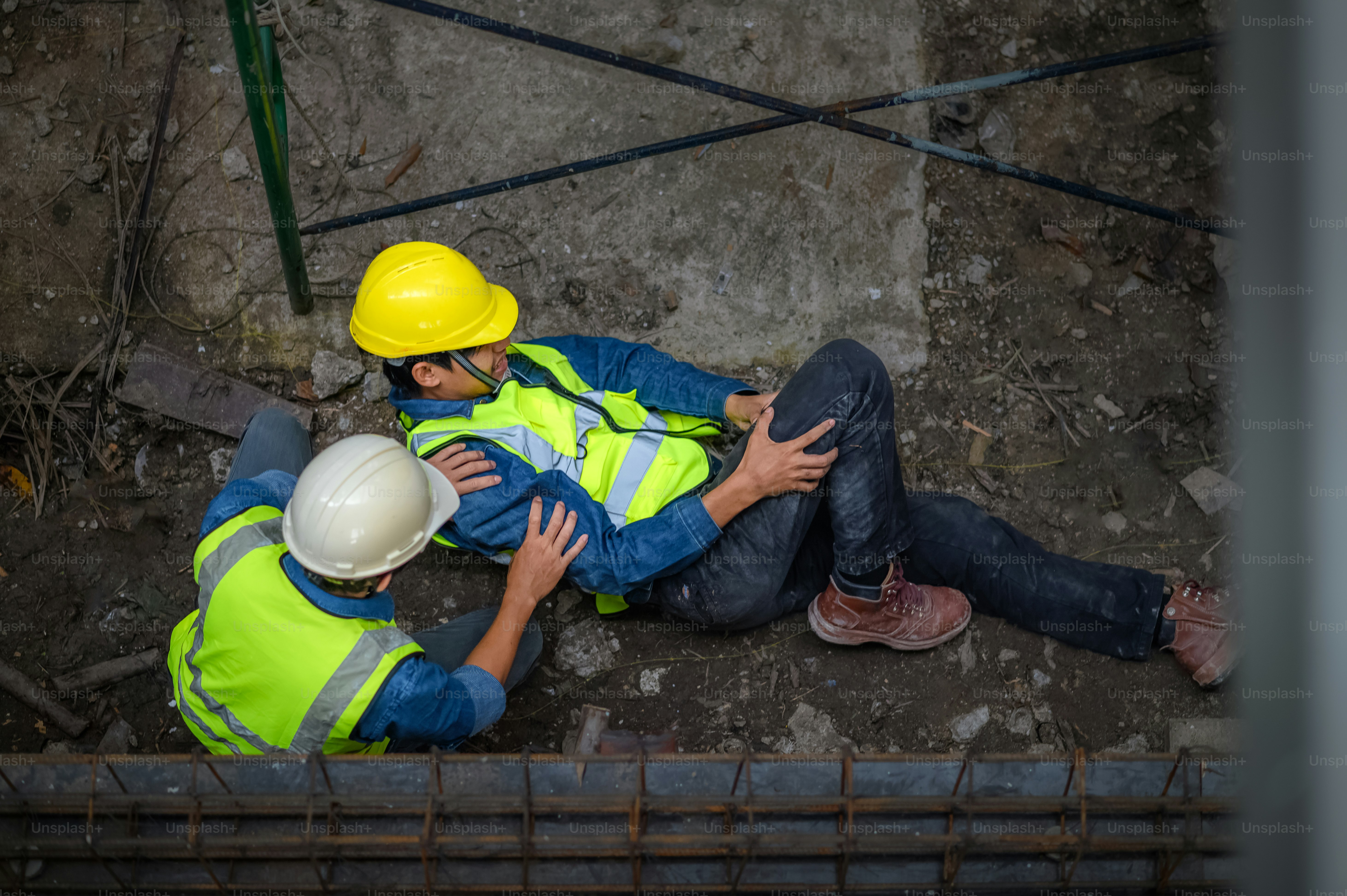 A young Asian builder falls from a scaffold at a construction site. An ...