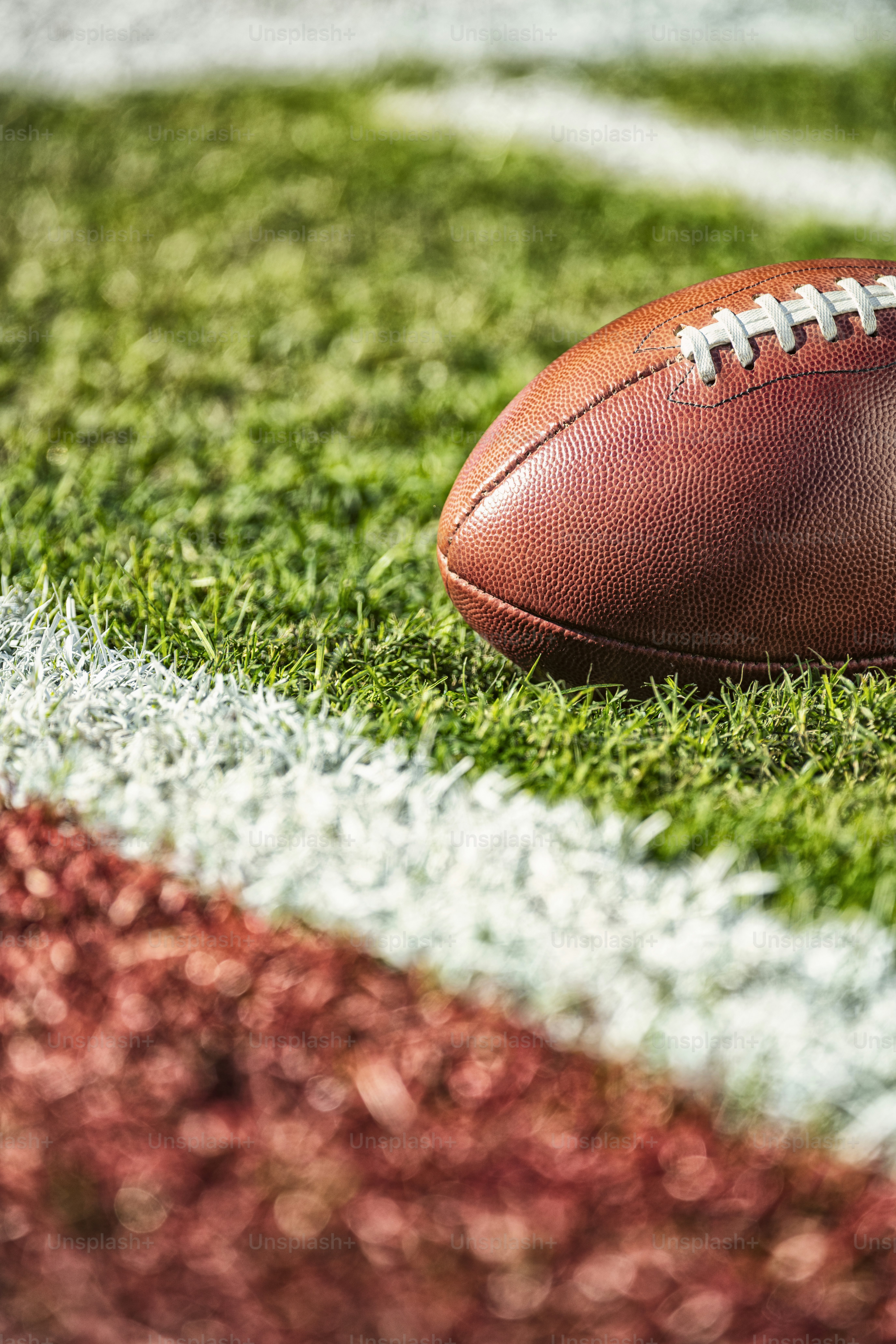 A low angle view of a leather American Football inches from the white ...