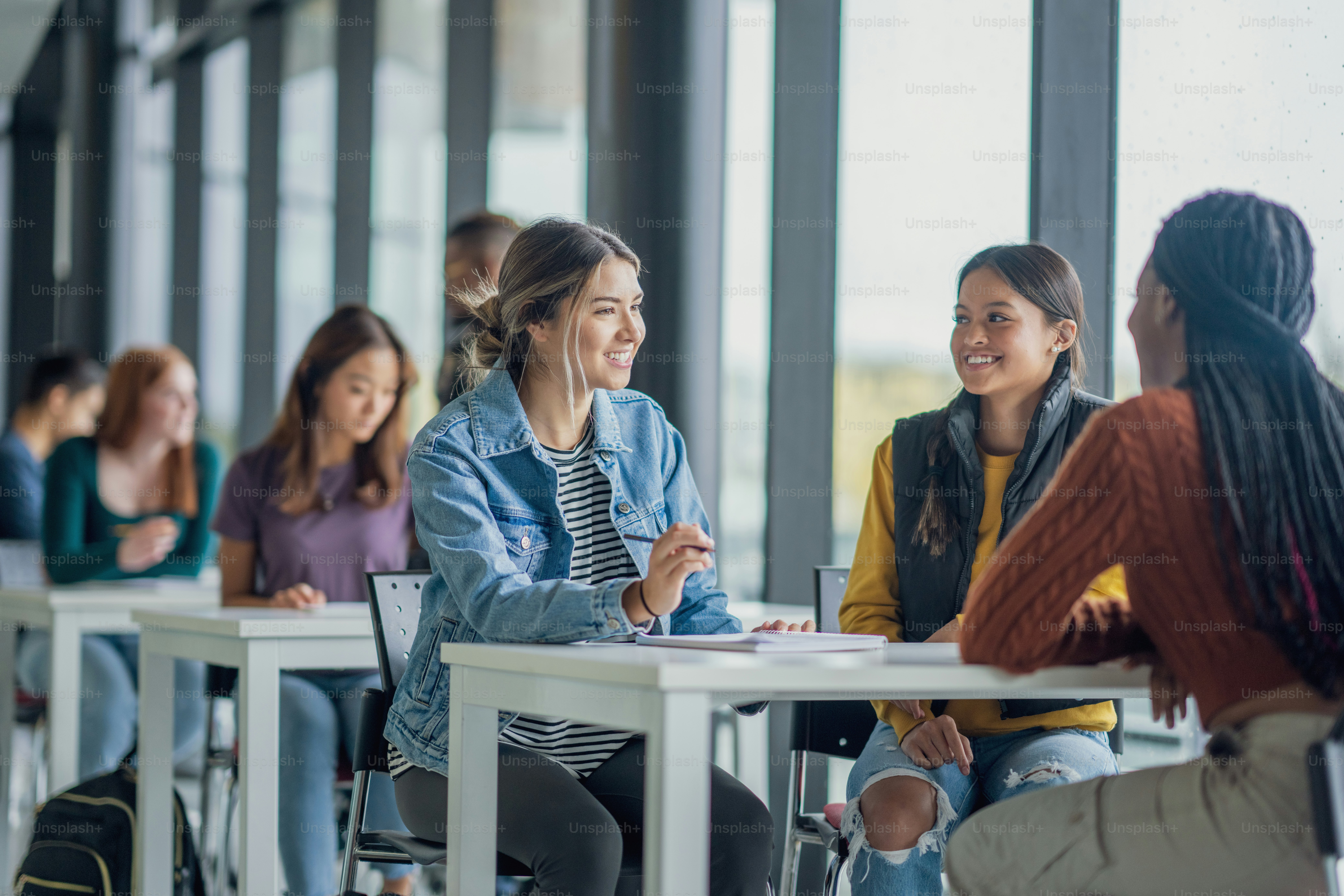 University students are seen scattered at various desks in an open ...