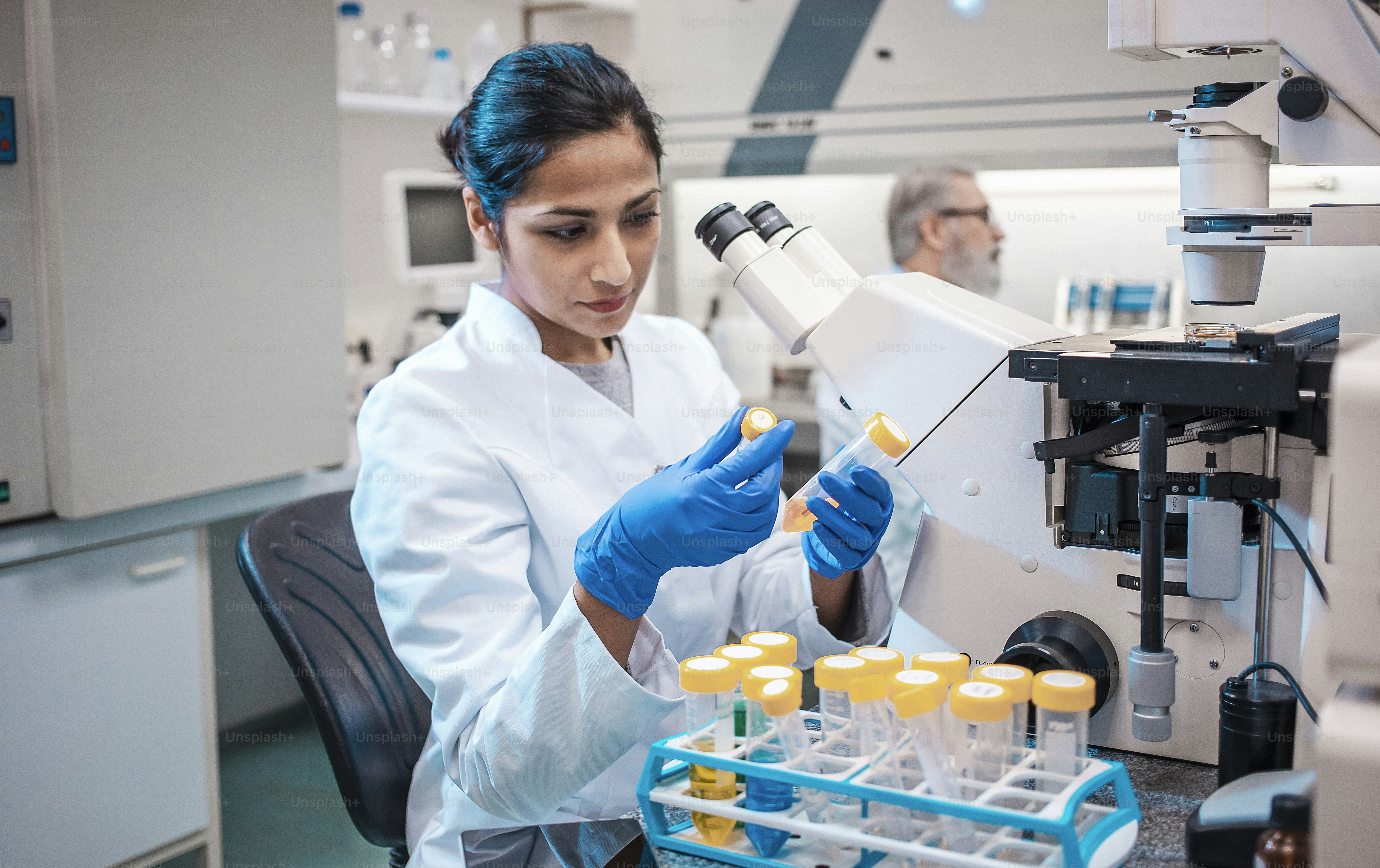 Mujer científica trabajando en el laboratorio, usando el microscopio ...