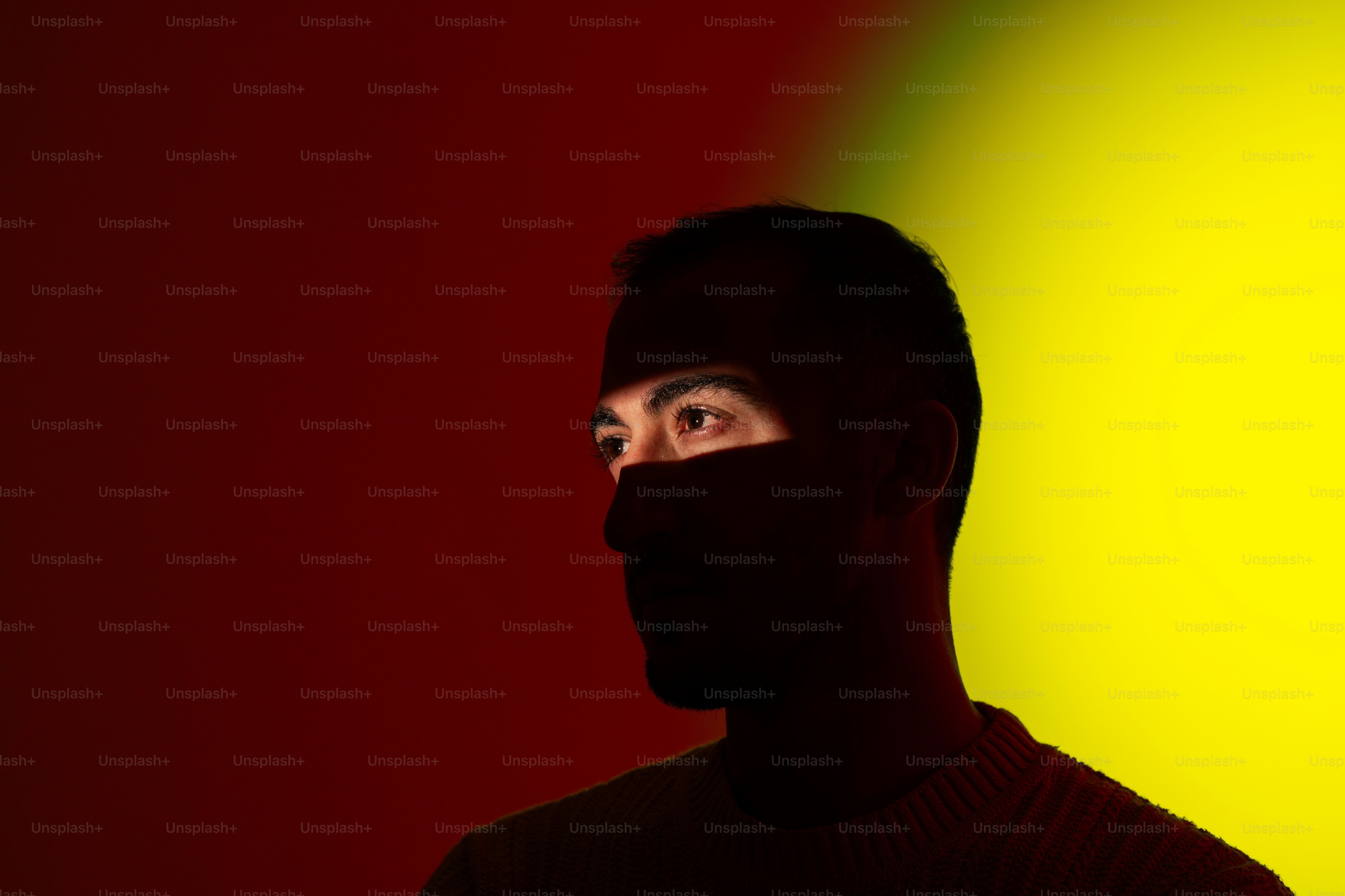 A man in a black hoodie and a yellow and red background photo ...