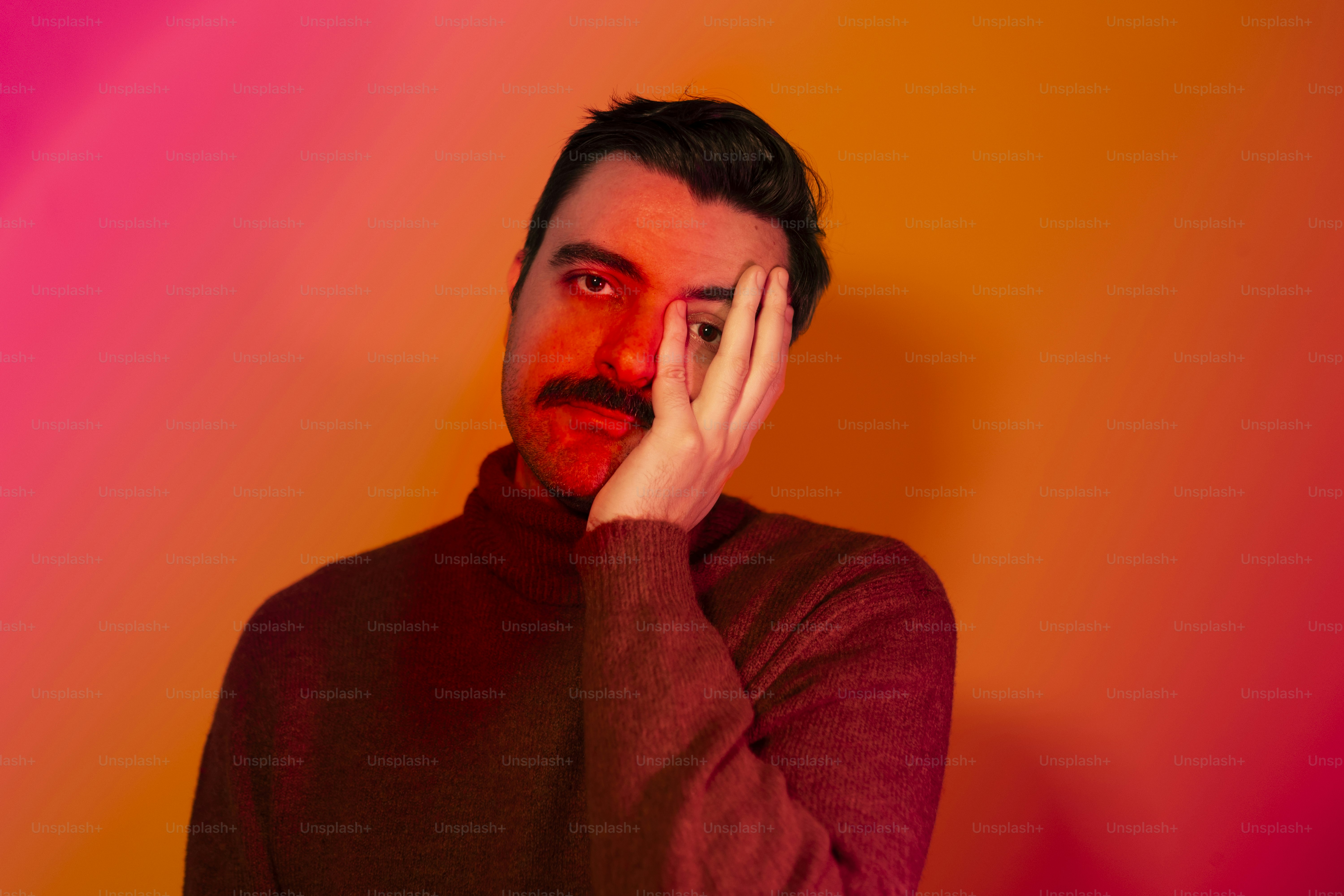A man in a red shirt is holding his hand to his face photo – Portrait ...
