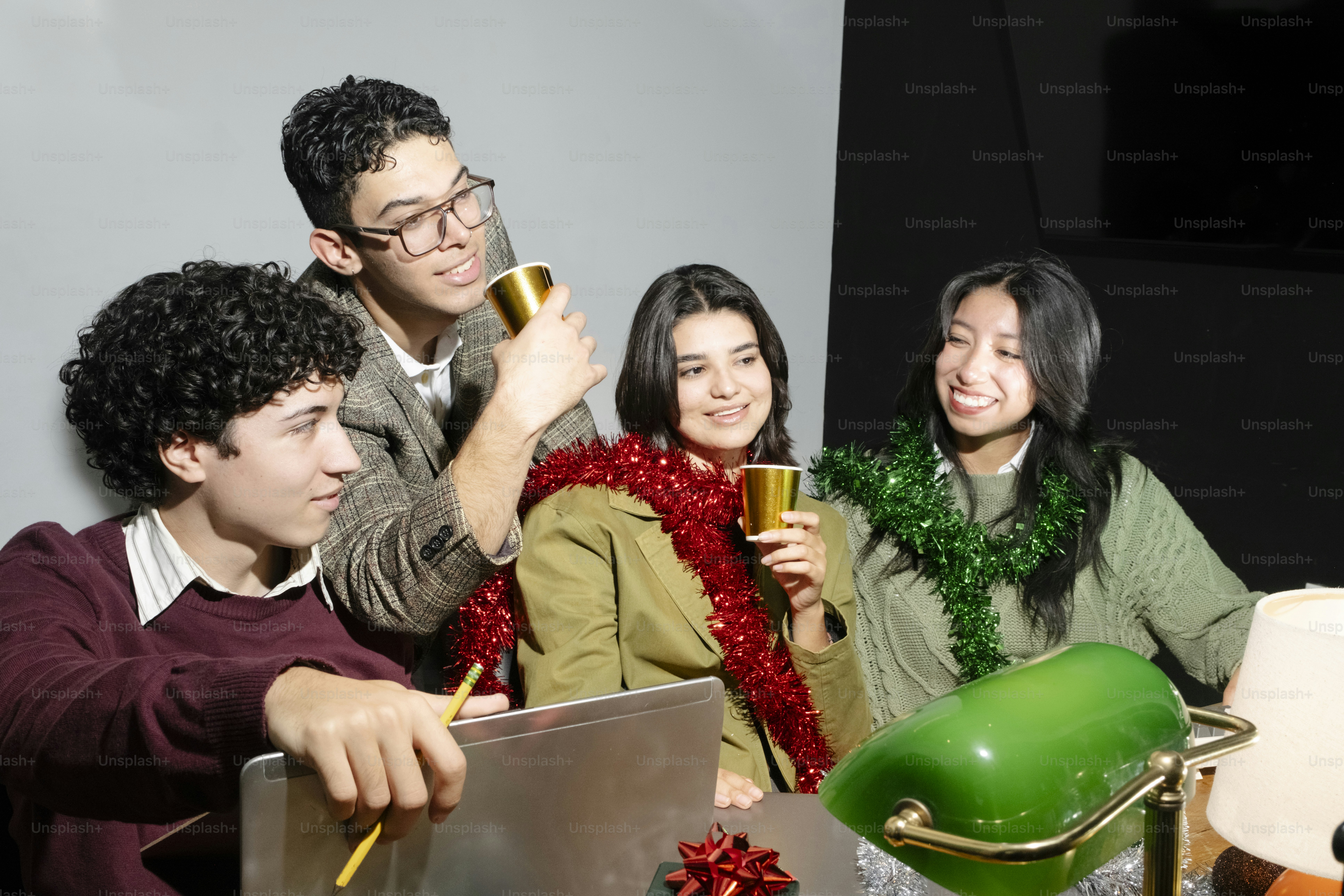 A group of people sitting around a laptop computer photo – Party Image ...