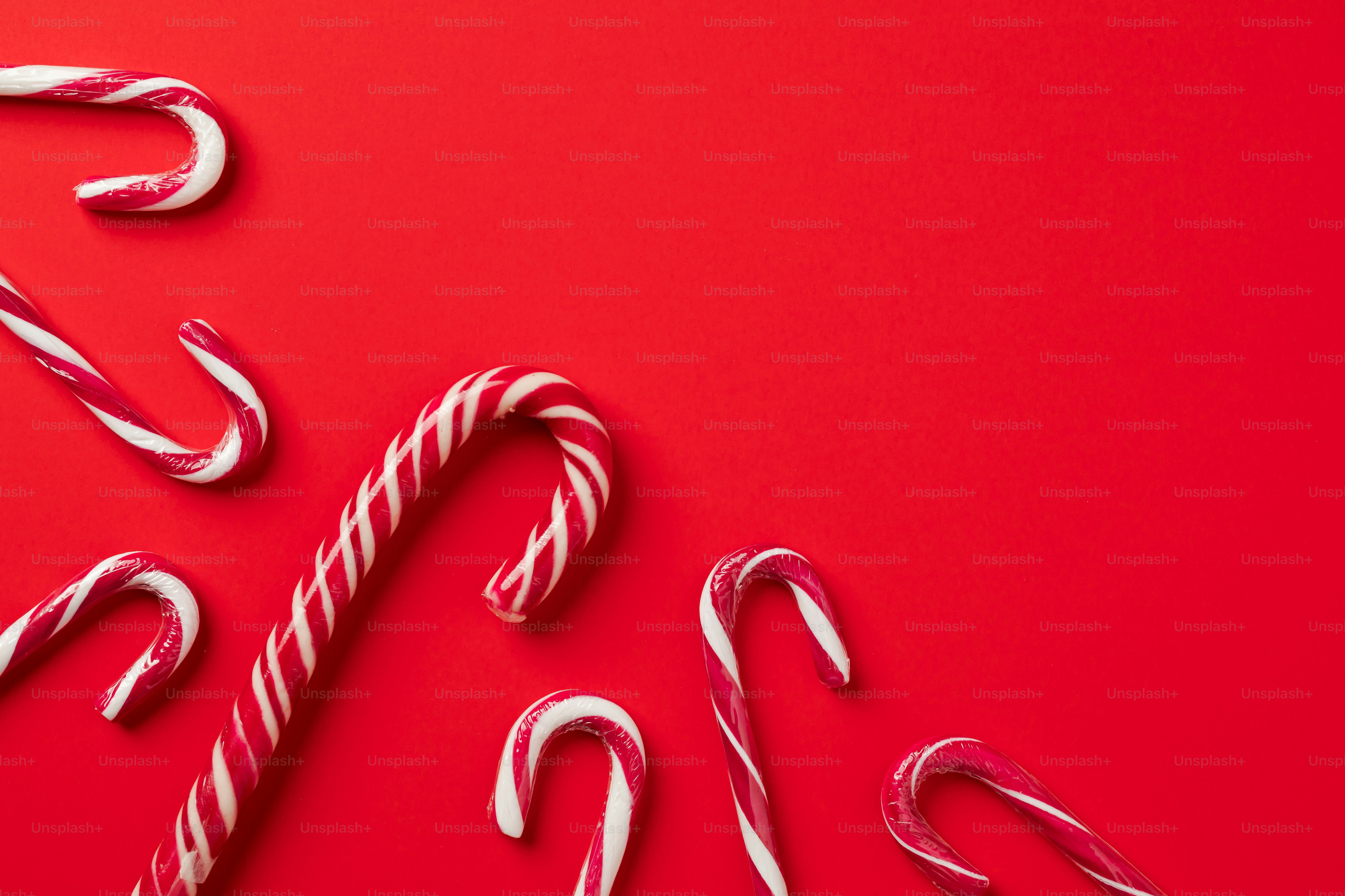 A candy cane and two candy canes on a red background photo – Modern ...