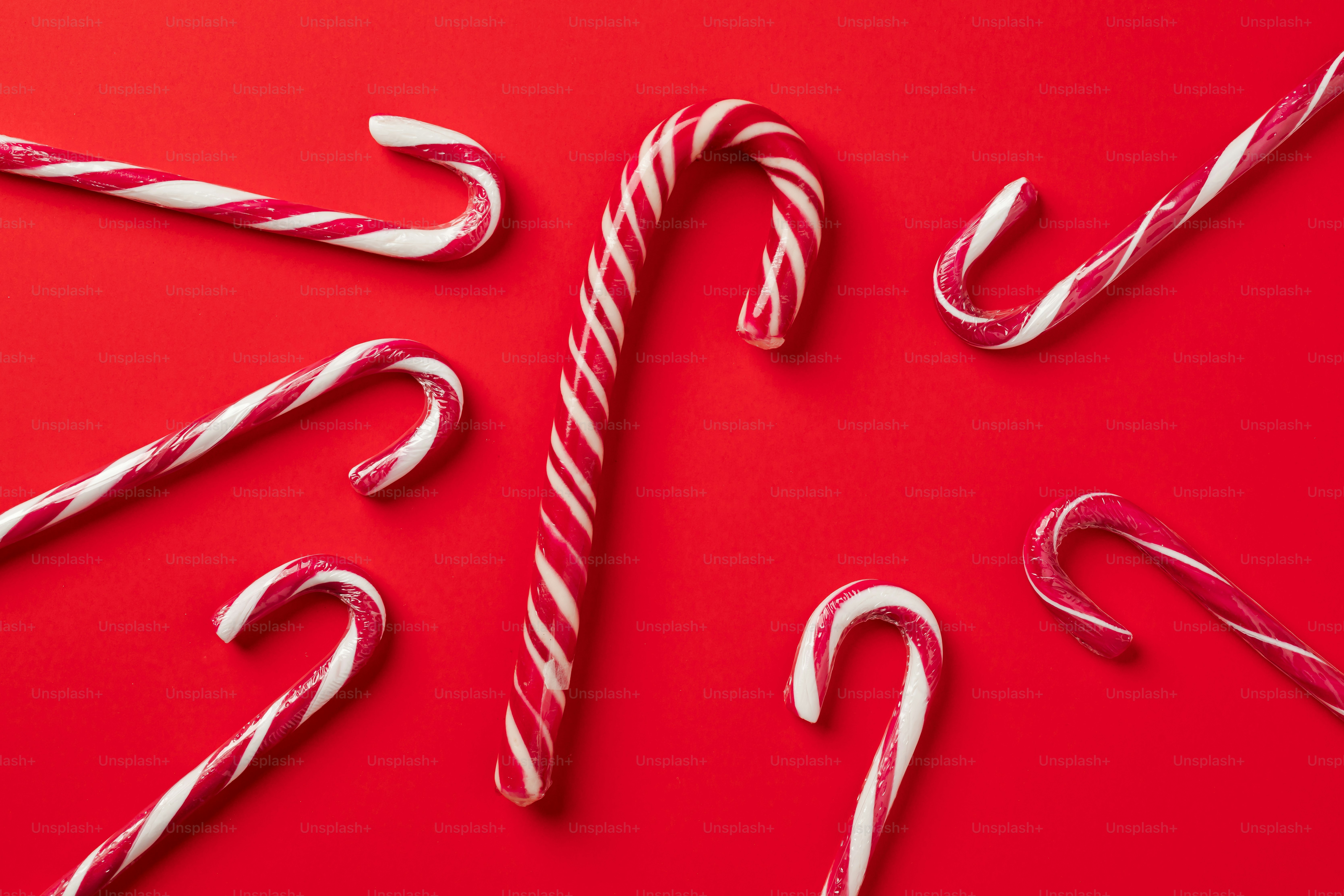 A candy cane and two candy canes on a red background photo – Modern ...