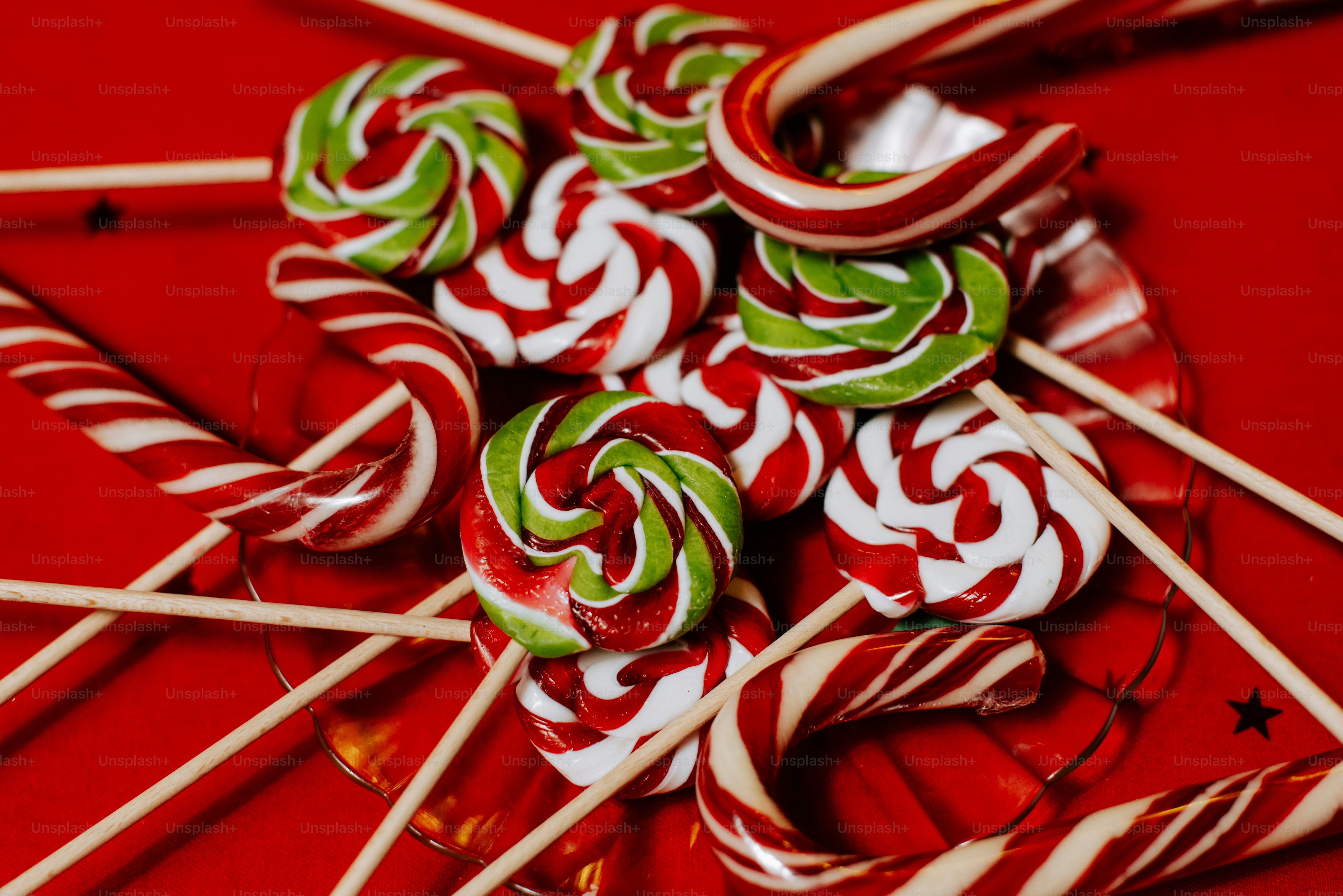 A pile of candy canes sitting on top of a red table photo – Modern ...
