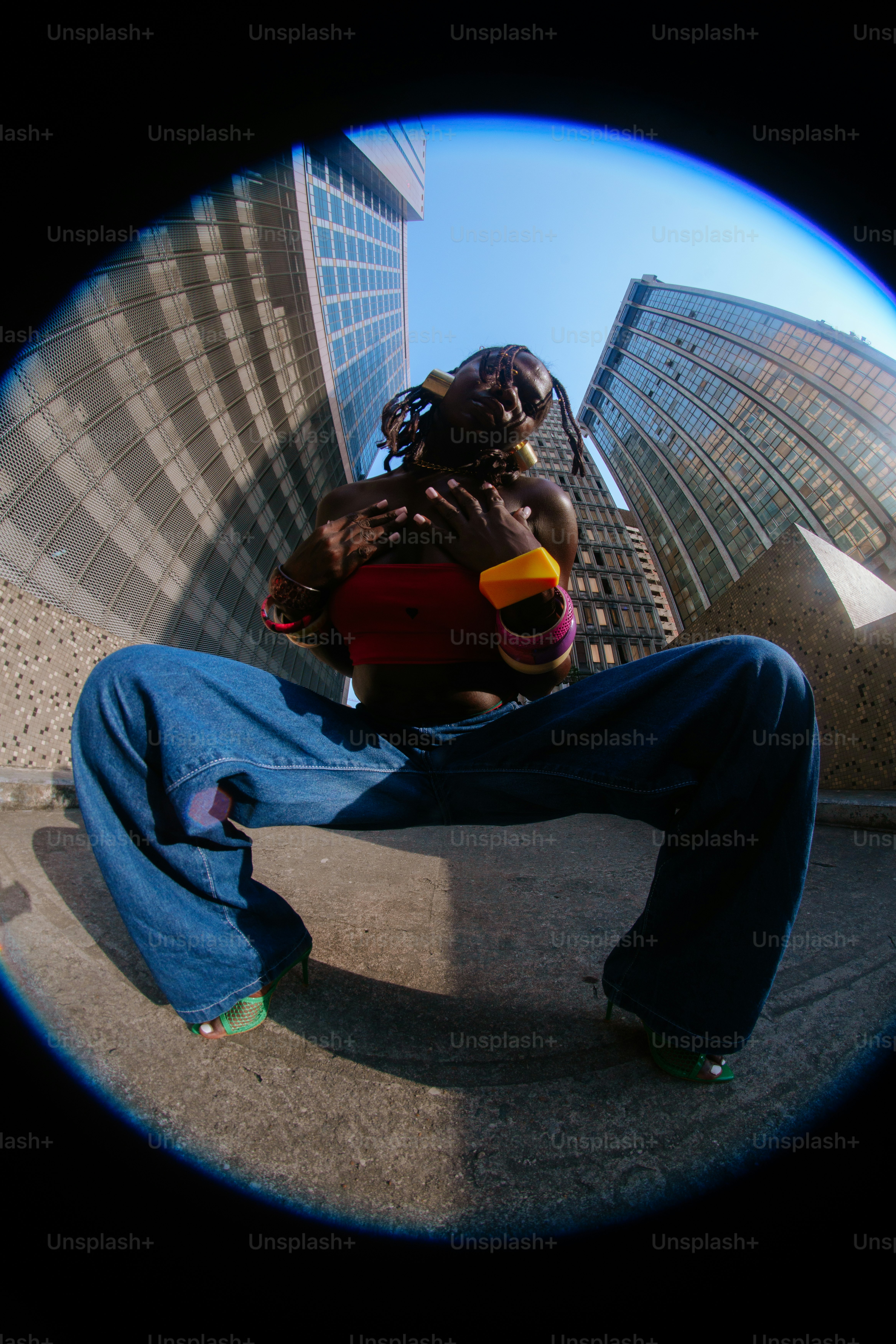 A man sitting on the ground in front of a tall building photo – Fashion ...