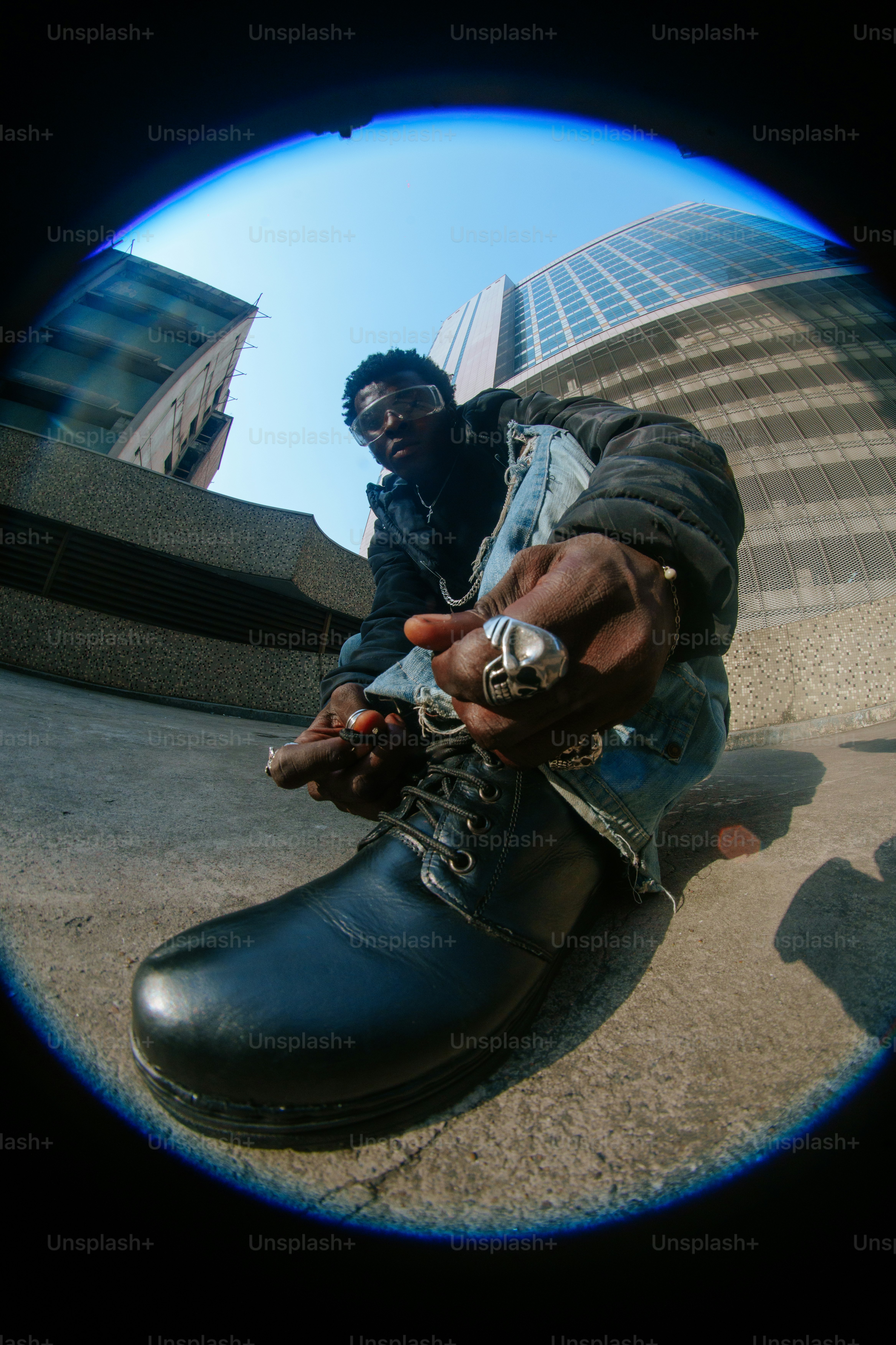 A man sitting on the ground in front of a tall building photo – Fashion ...
