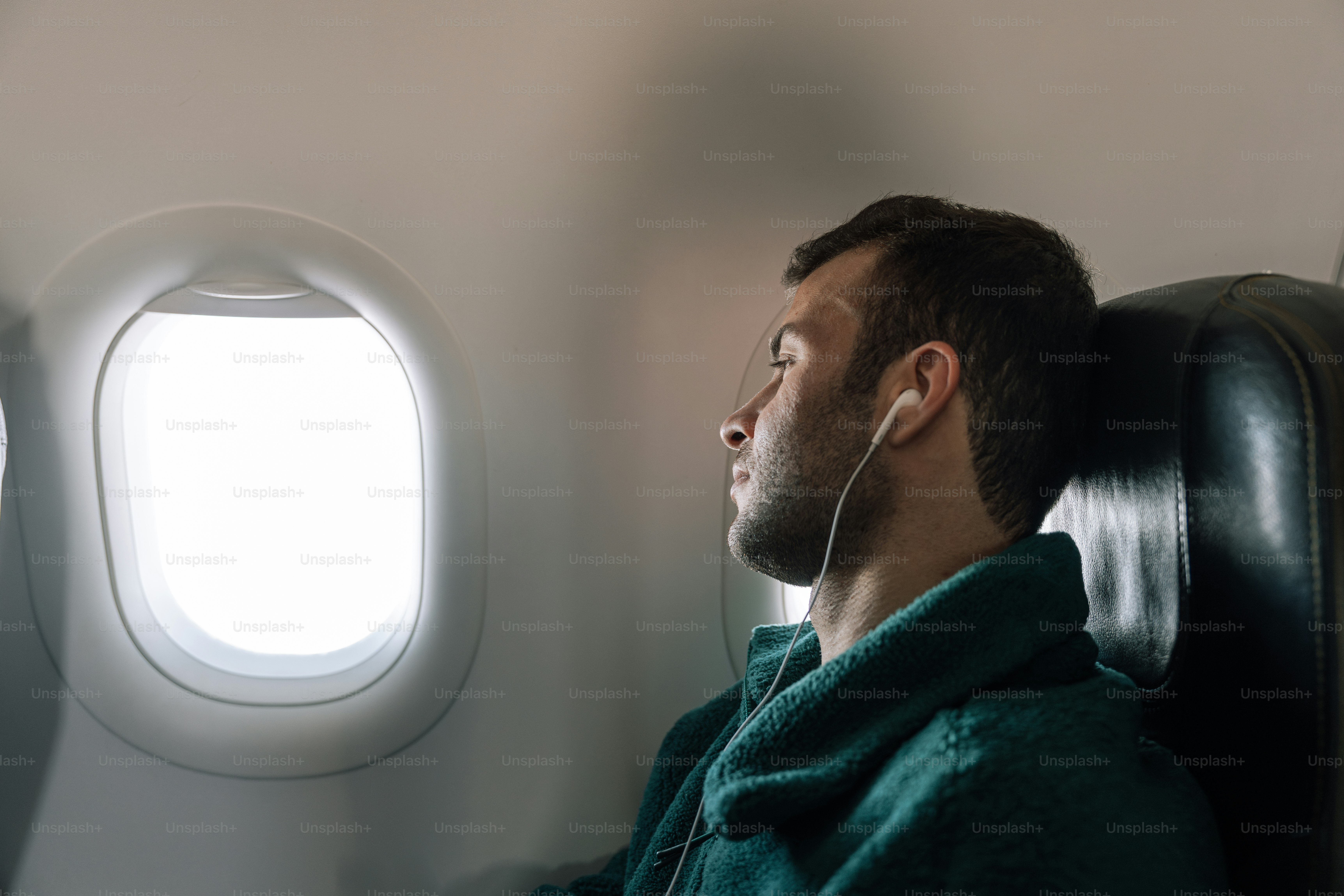A man sitting in an airplane looking out the window photo – Travel ...