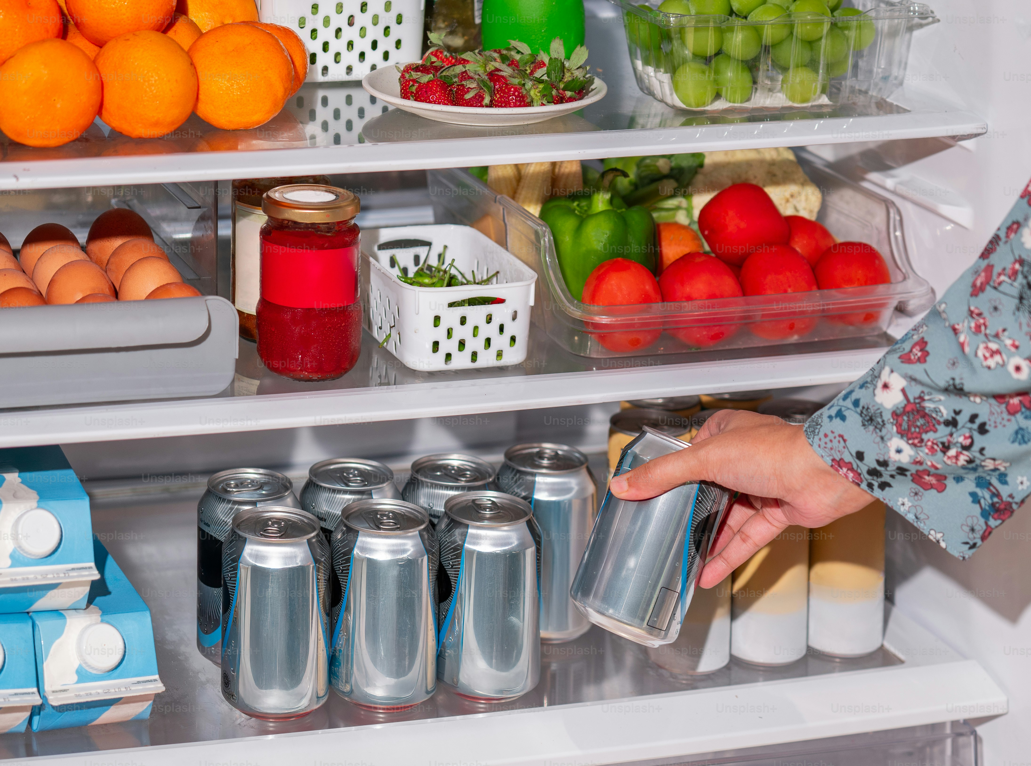 A person reaching into an open refrigerator filled with food photo ...