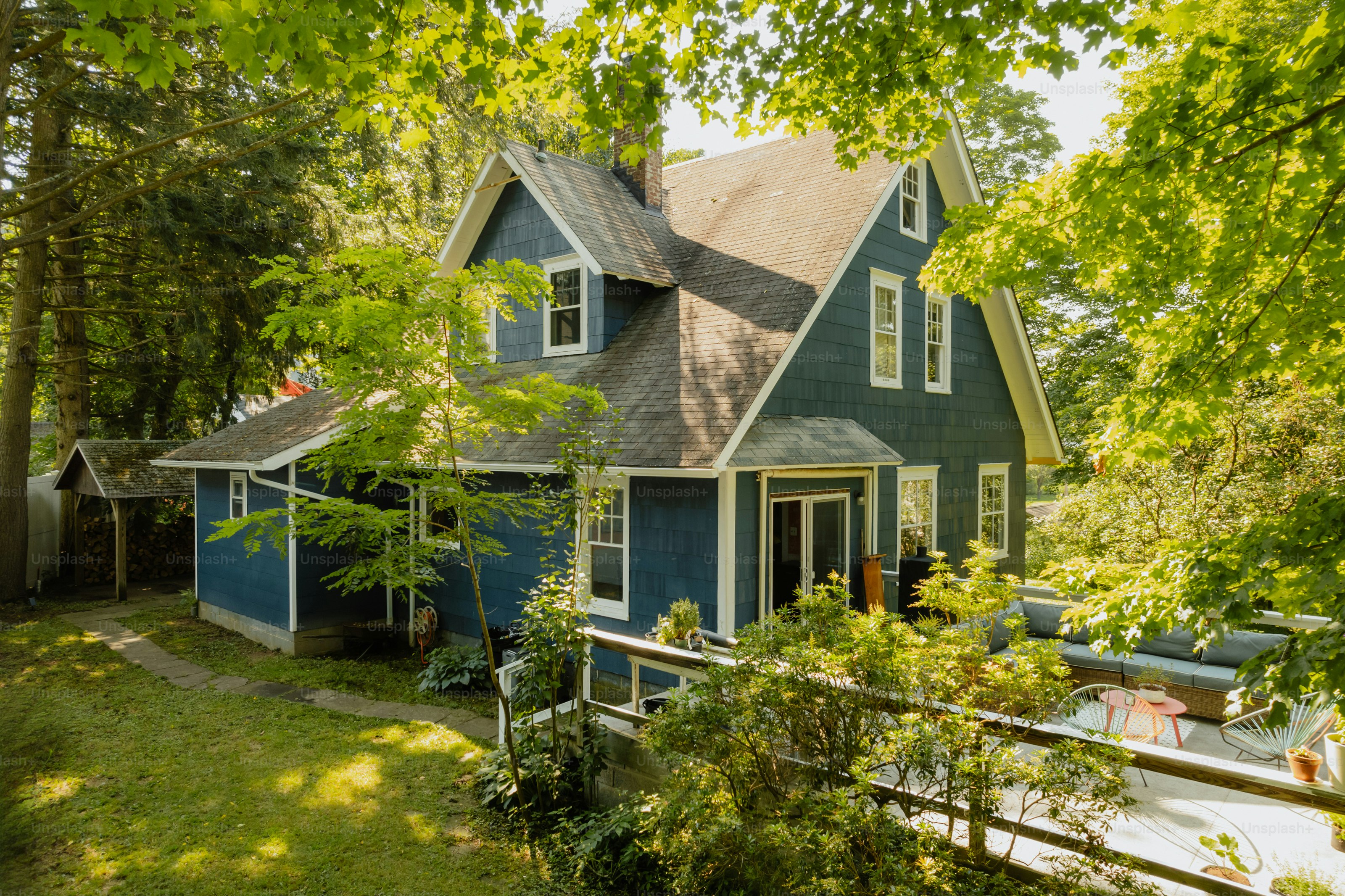 A blue house surrounded by trees and grass photo – Property Image on ...