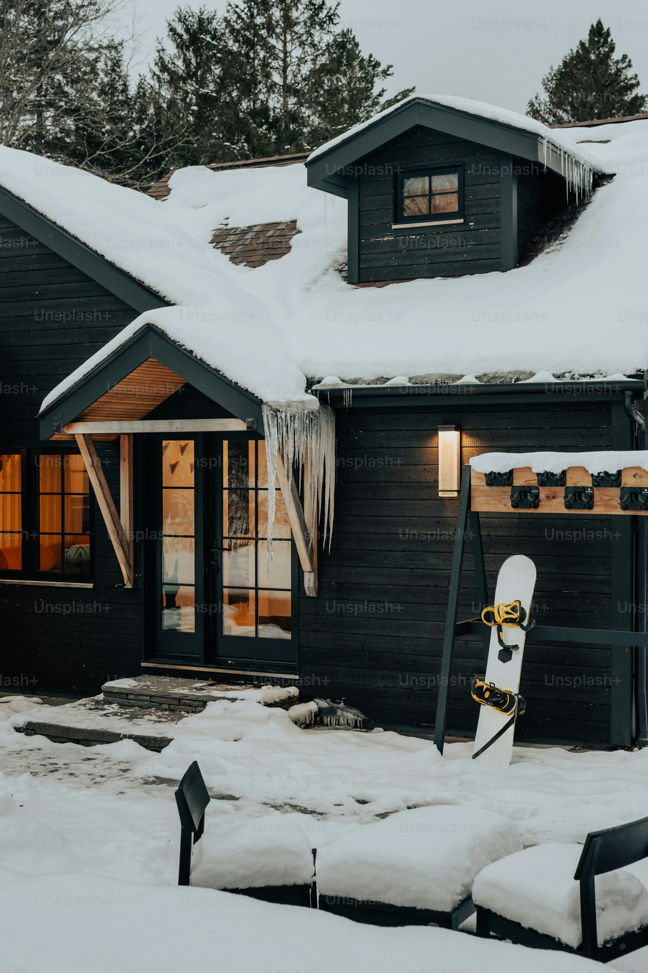 A house covered in snow with a snowboard in front of it photo ...