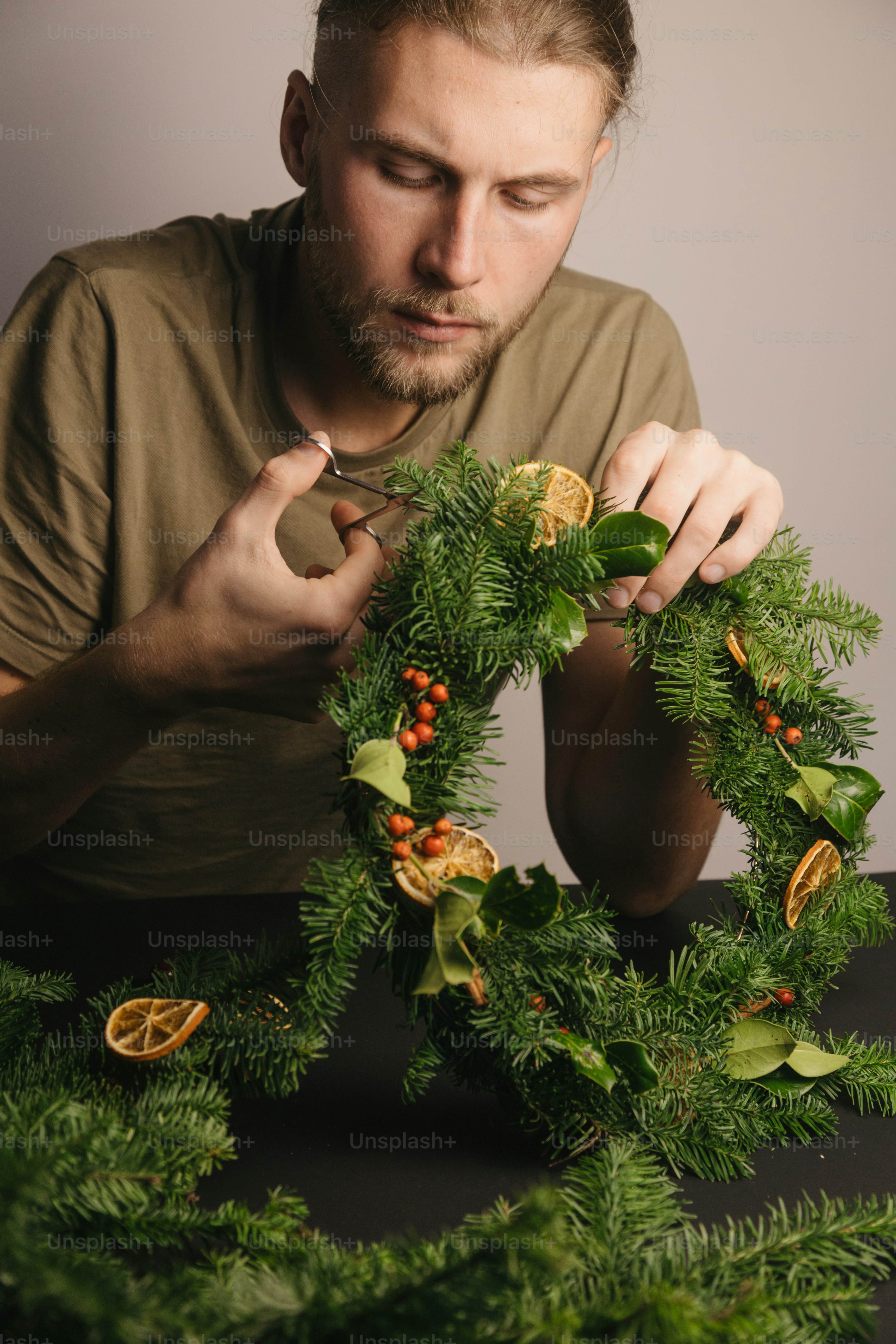A man is making a wreath out of branches photo – Christmas Image on ...