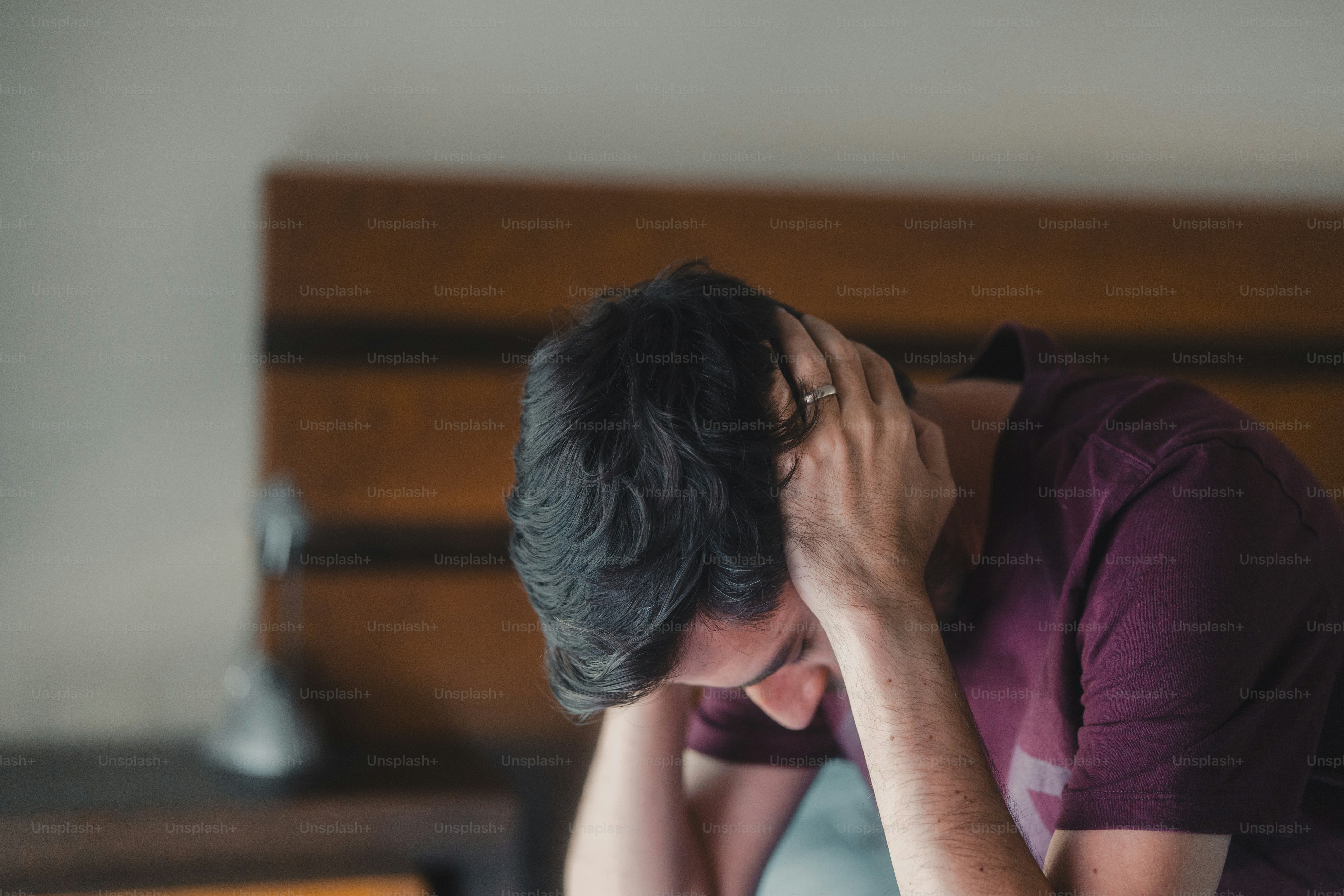 A man sitting on a bed with his head in his hands photo – Mens mental ...