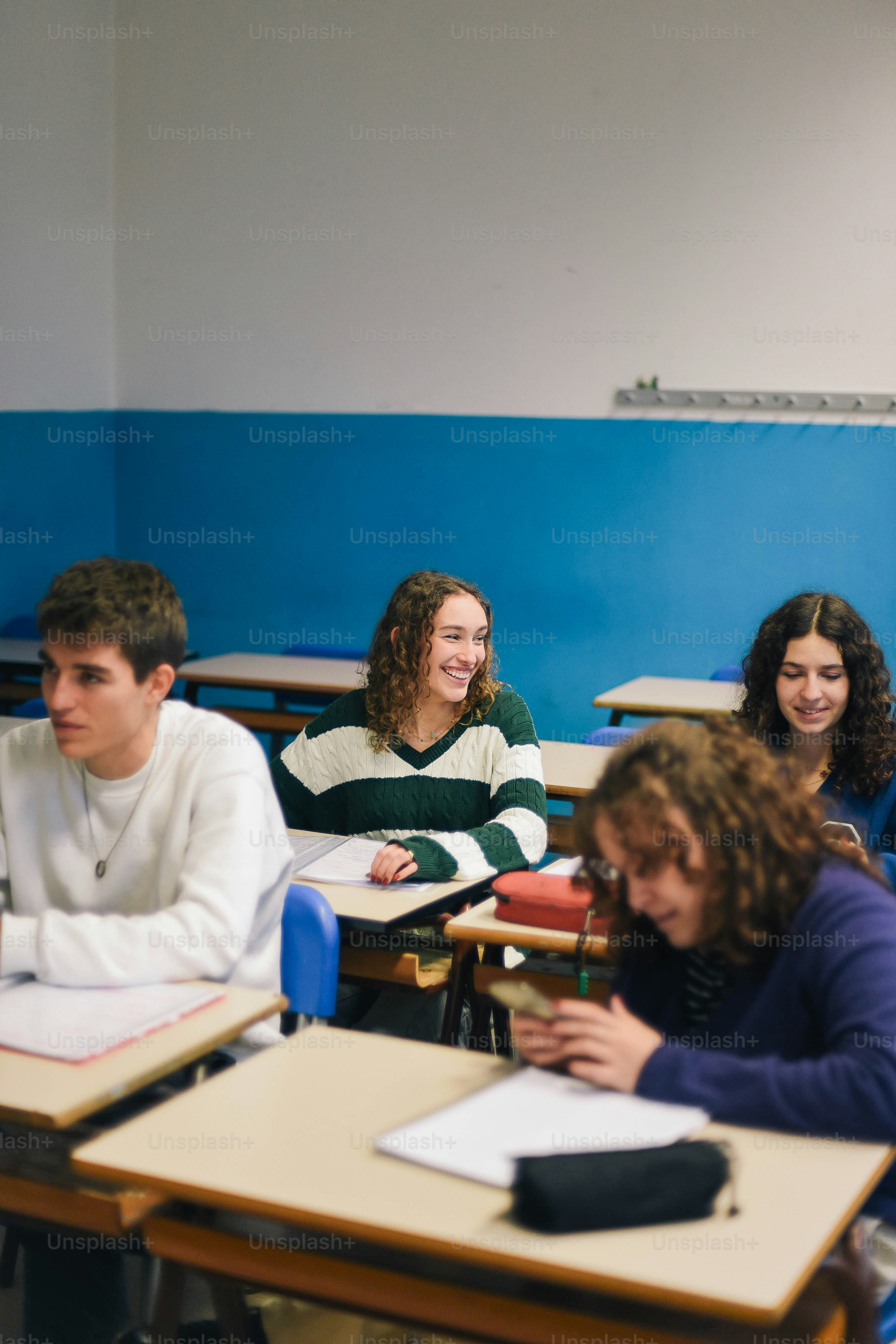 A group of people sitting at desks in a classroom photo – Students ...