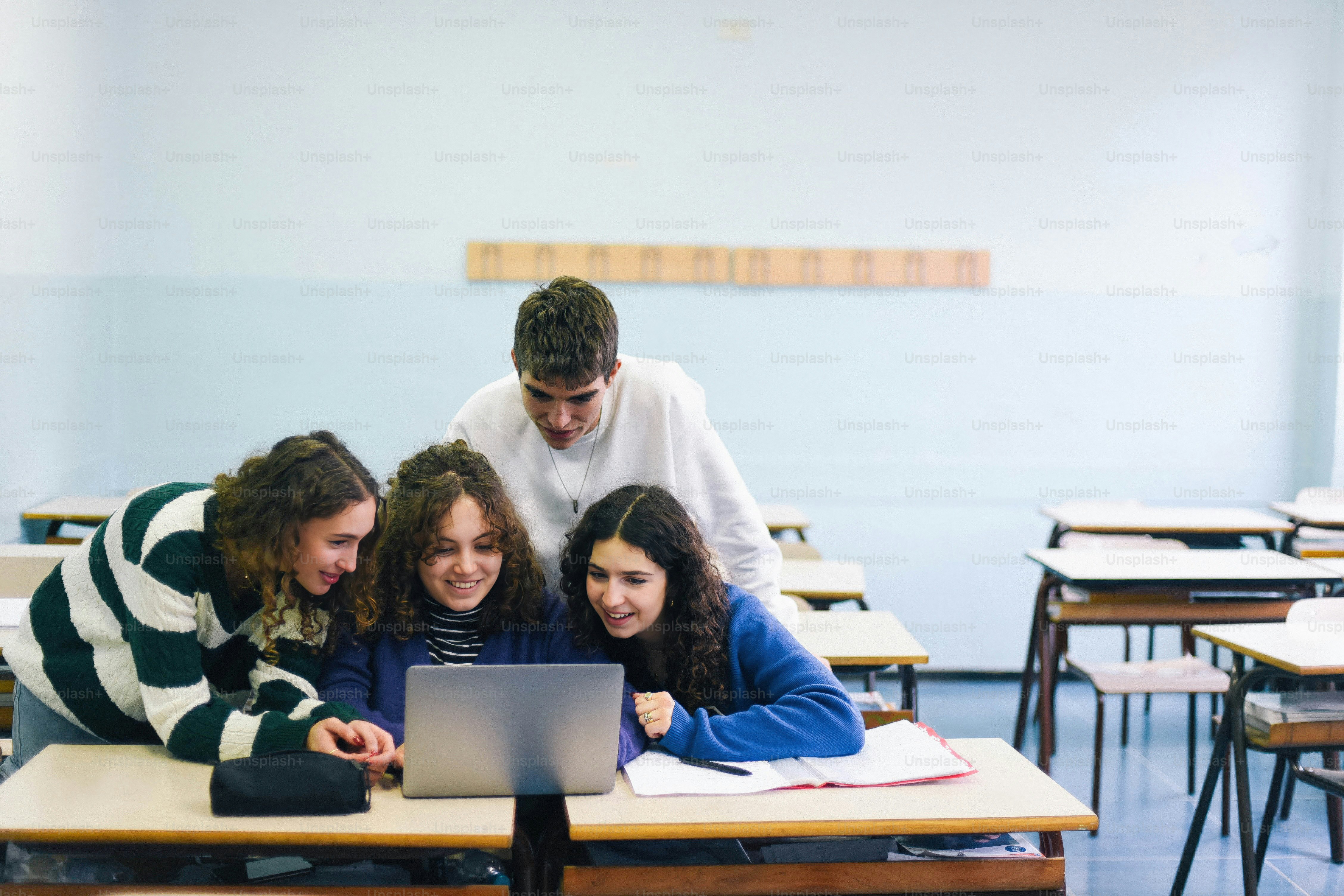 A group of young people sitting at desks in a classroom photo – School ...