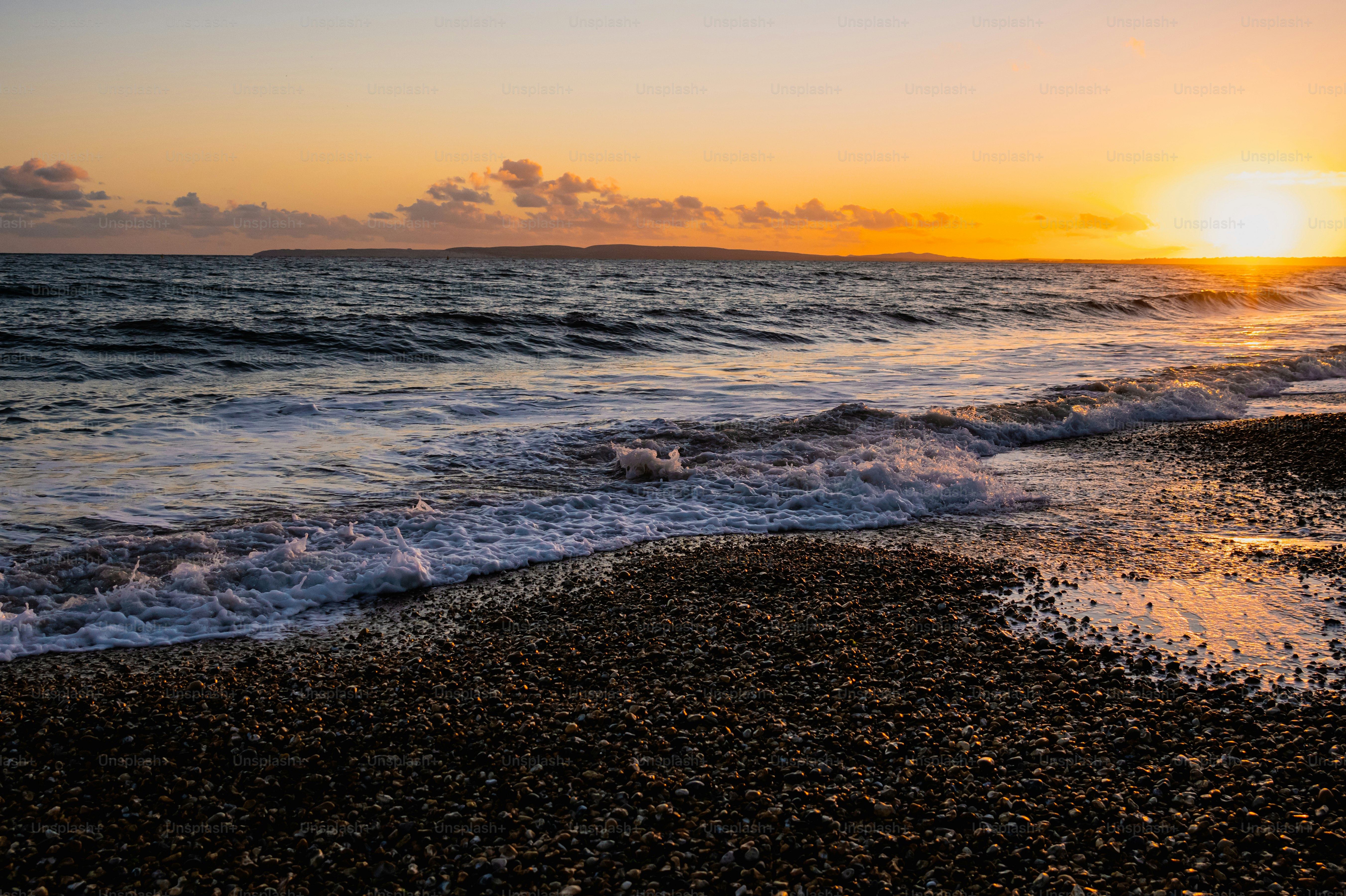 The sun is setting over the ocean on the beach photo – Sunset Image on ...