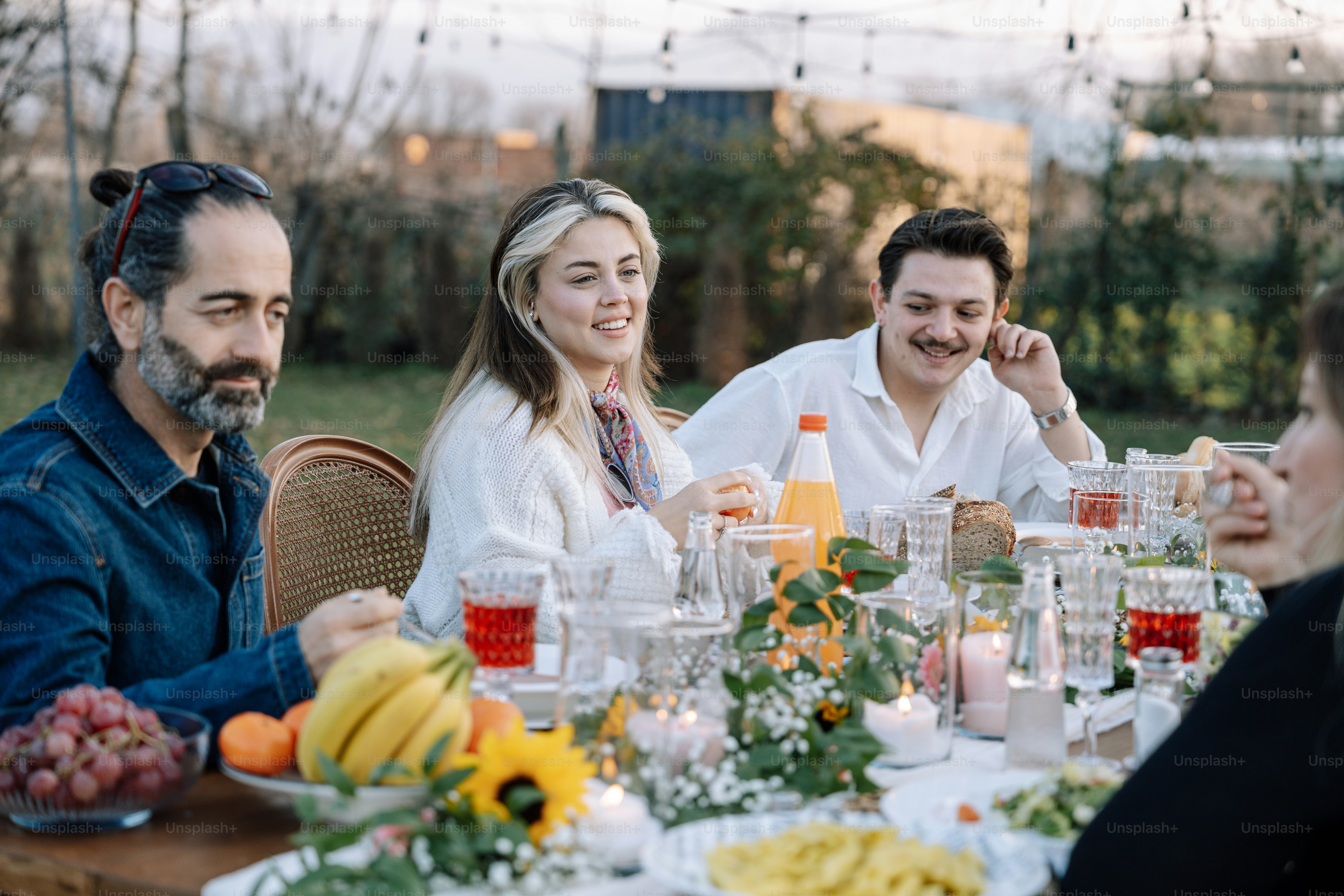 A group of people sitting around a table with candles photo – Dinner ...
