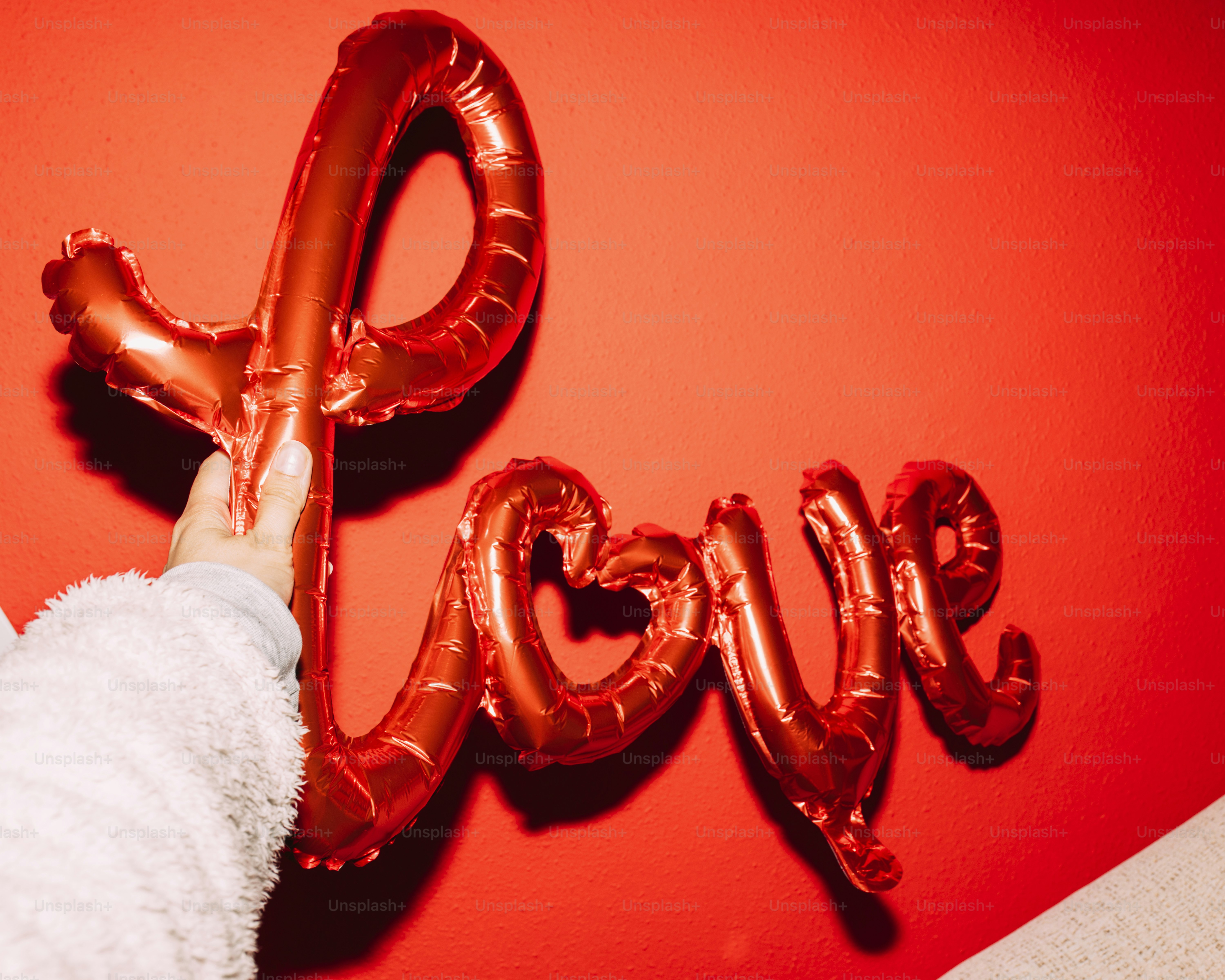 A person holding a balloon in the shape of the word love photo ...