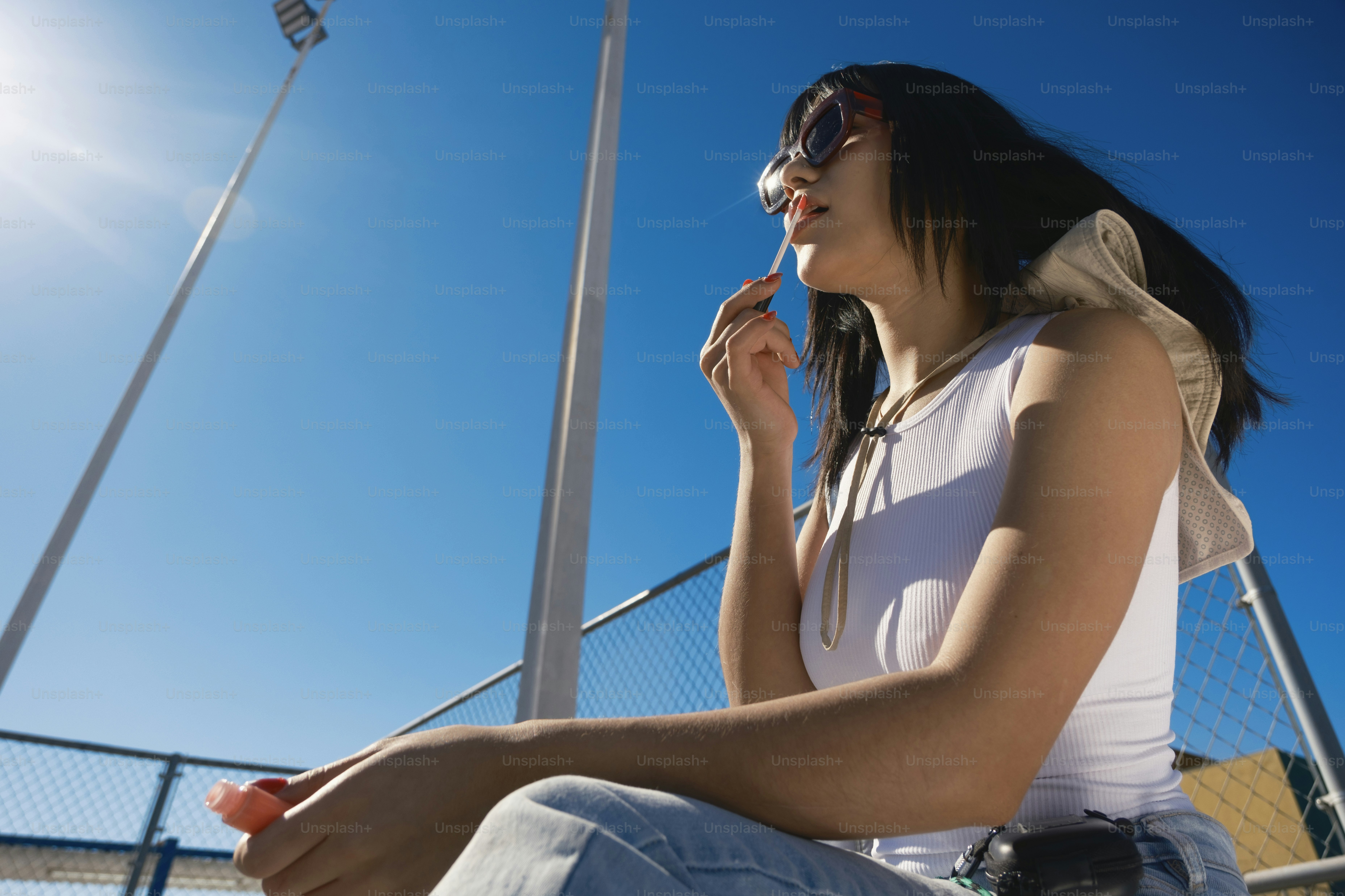 A woman sitting on a railing smoking a cigarette photo – Gen z Image on ...