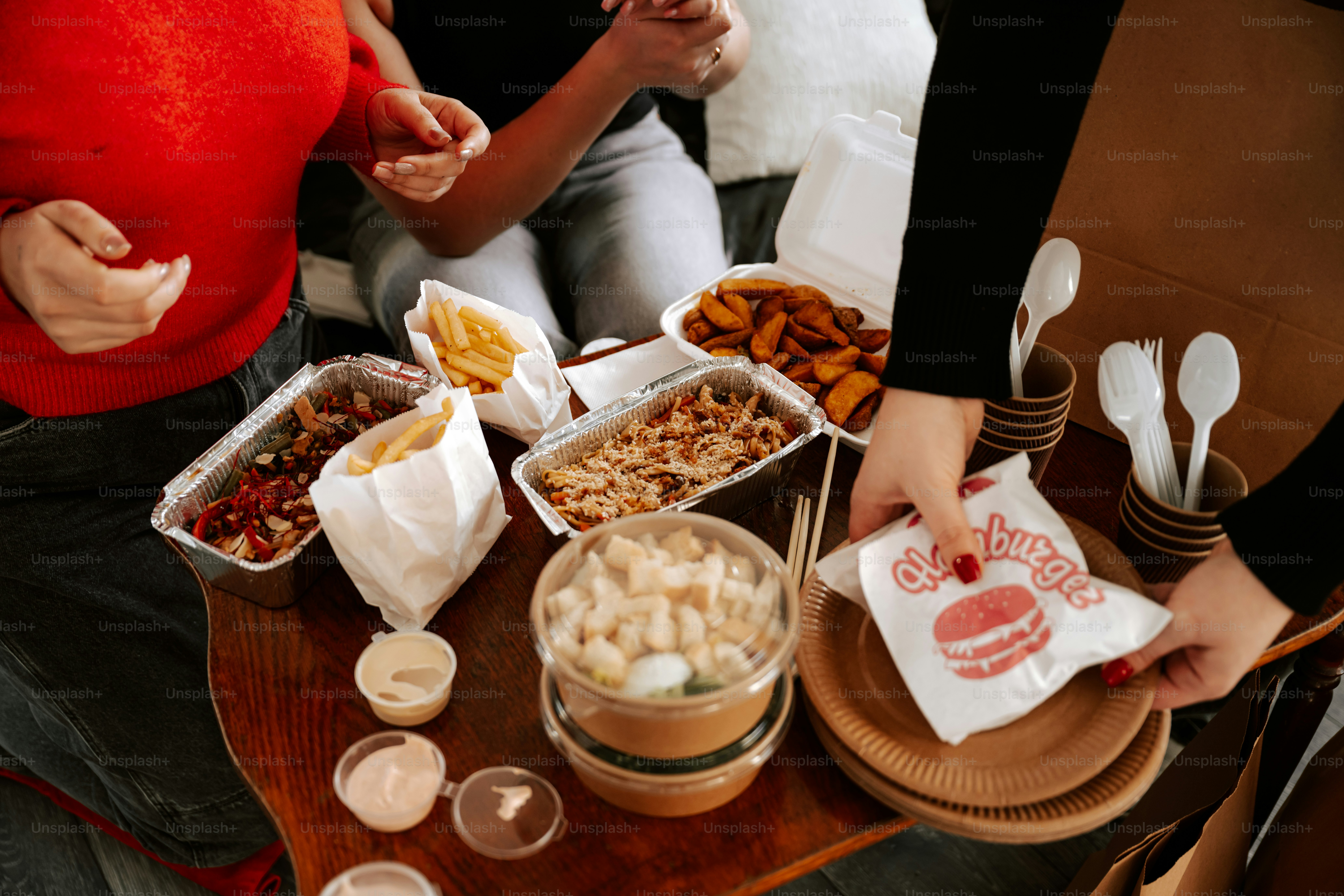 Eine Gruppe von Menschen, die um einen Tisch voller Essen sitzen Foto ...